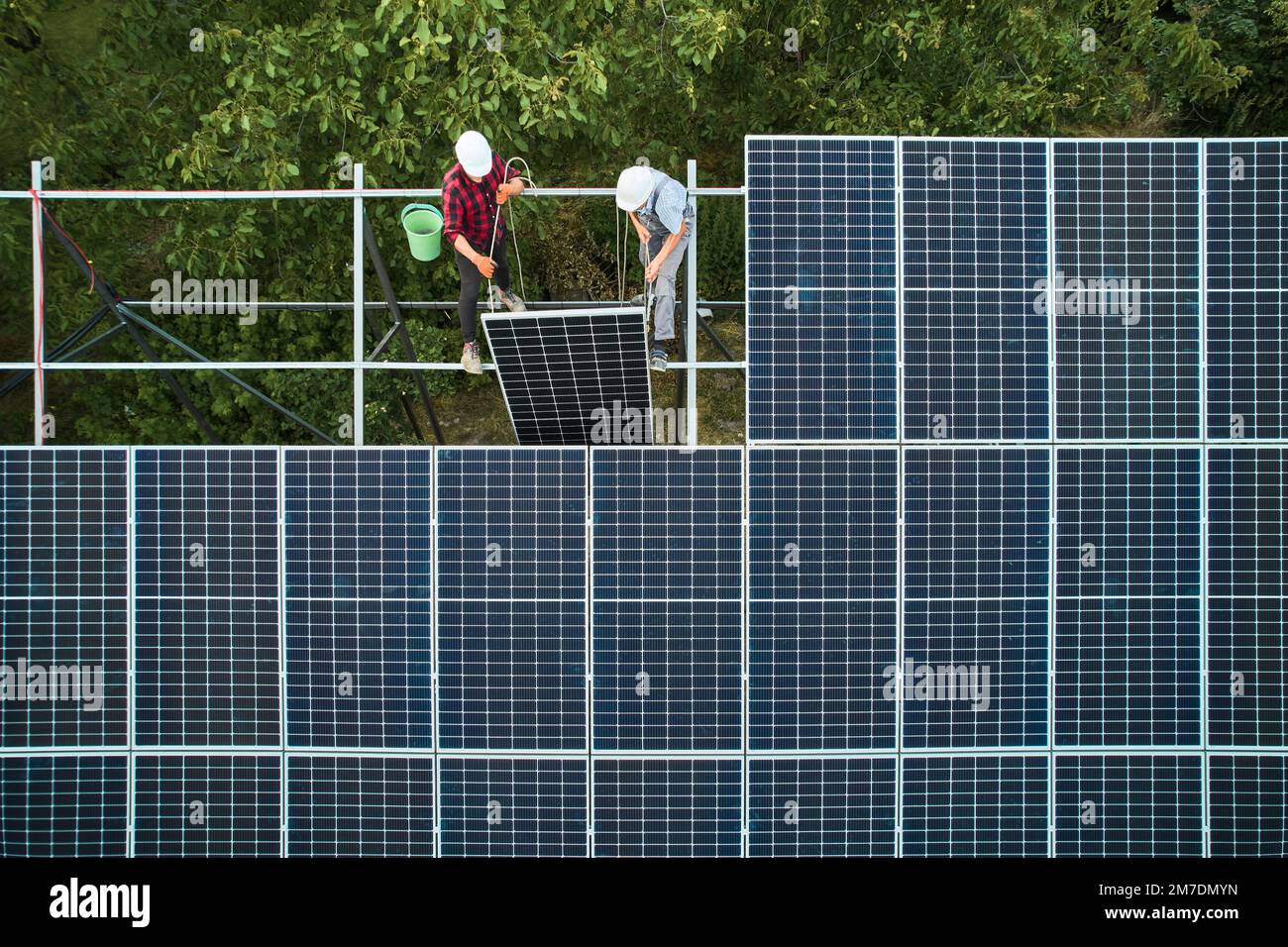 Workers holding and installing solar panels. Men wear helmets and ...