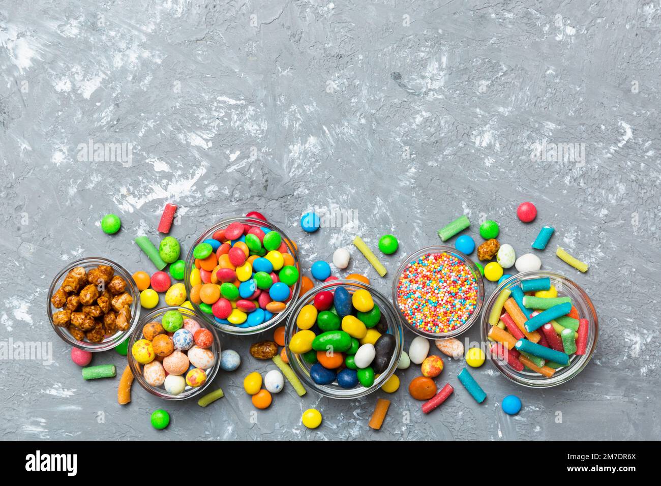 different colored round candy in bowl and jars. Top view of large ...