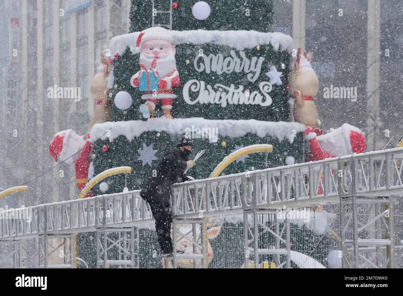 A man works in the snow near a Christmas tree for the upcoming ...