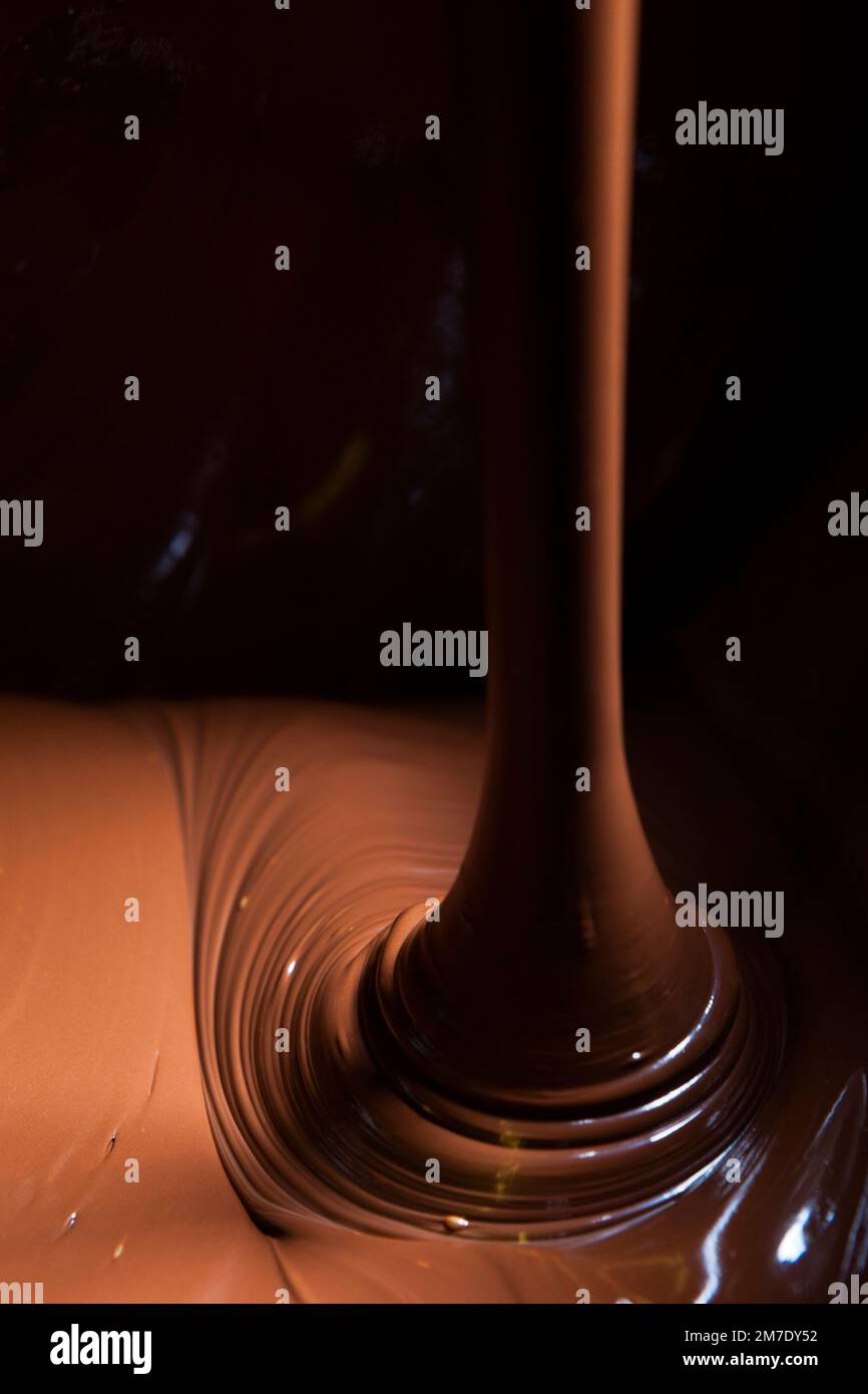 Liquid chocolate pouring into vats and tubes from pipes at a choclate ...