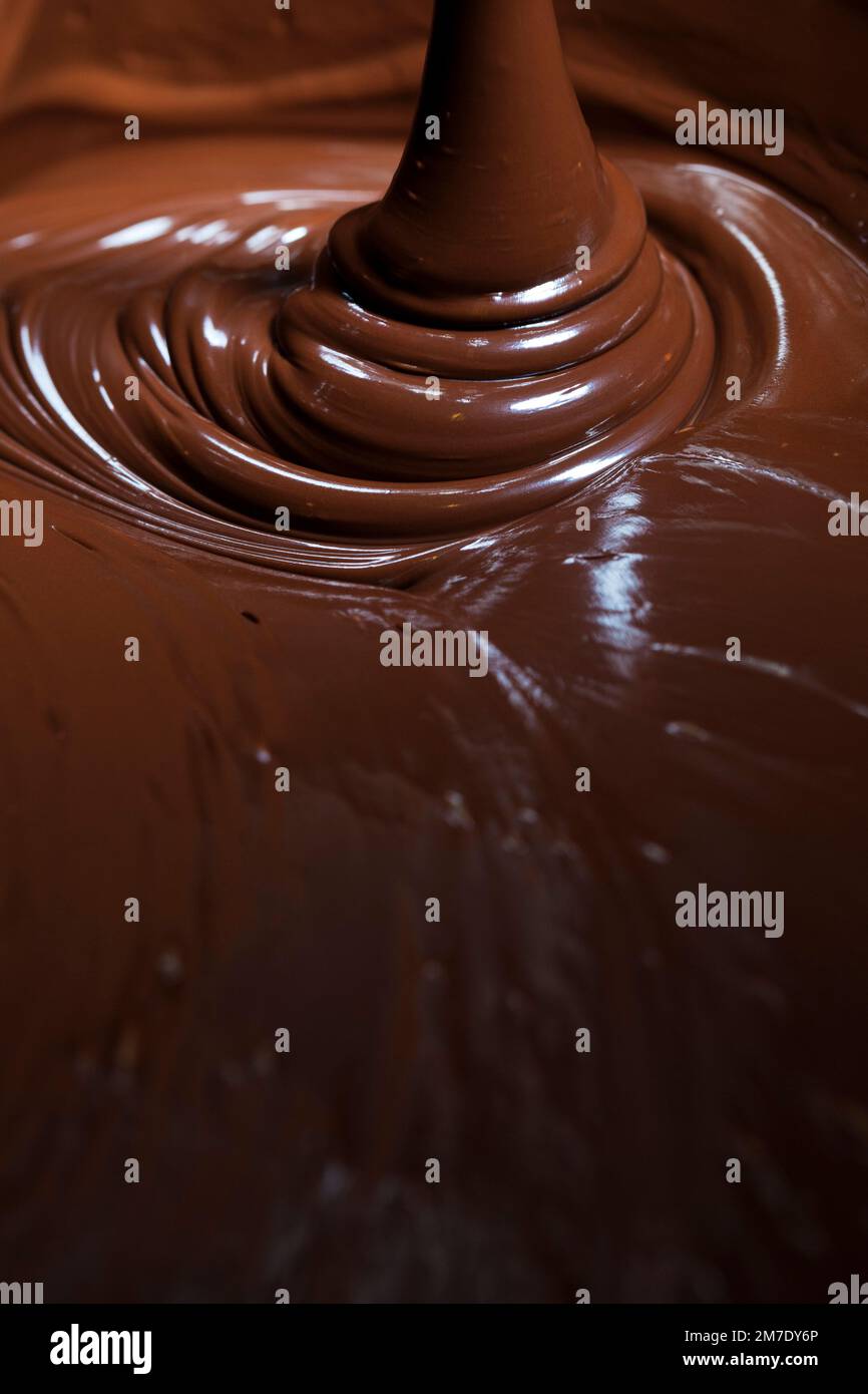 Liquid chocolate pouring into vats and tubes from pipes at a choclate ...