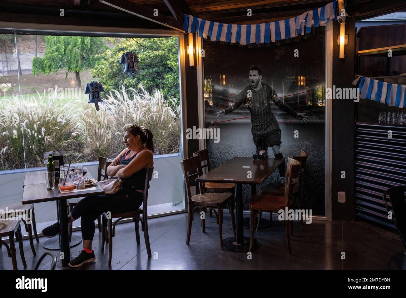 A woman eats lunch next to a picture of Lionel Messi inside a ...