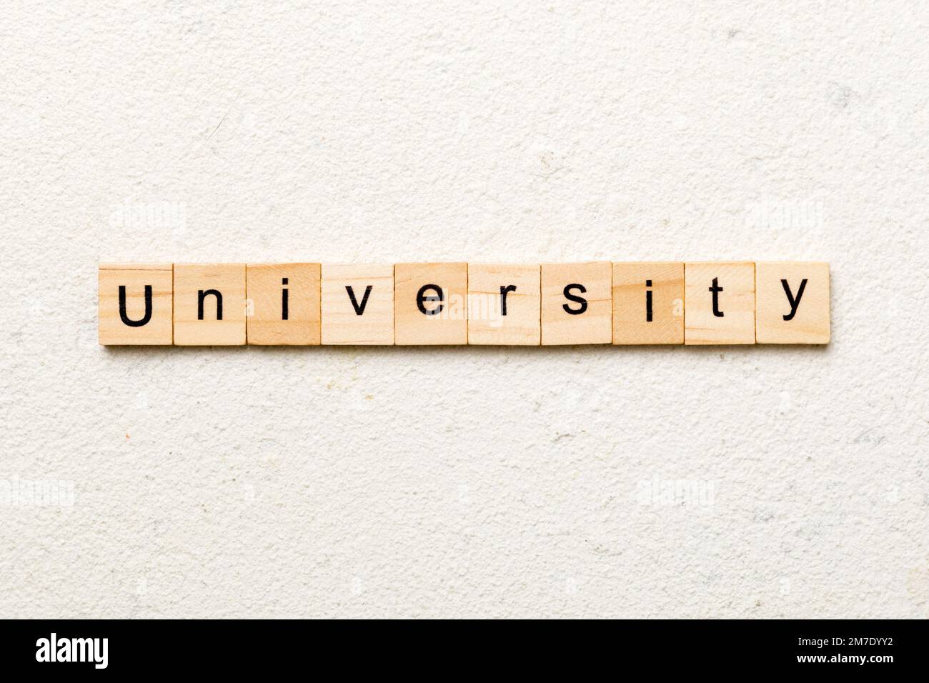 UNIVERSITY word written on wood block. UNIVERSITY text on cement table ...