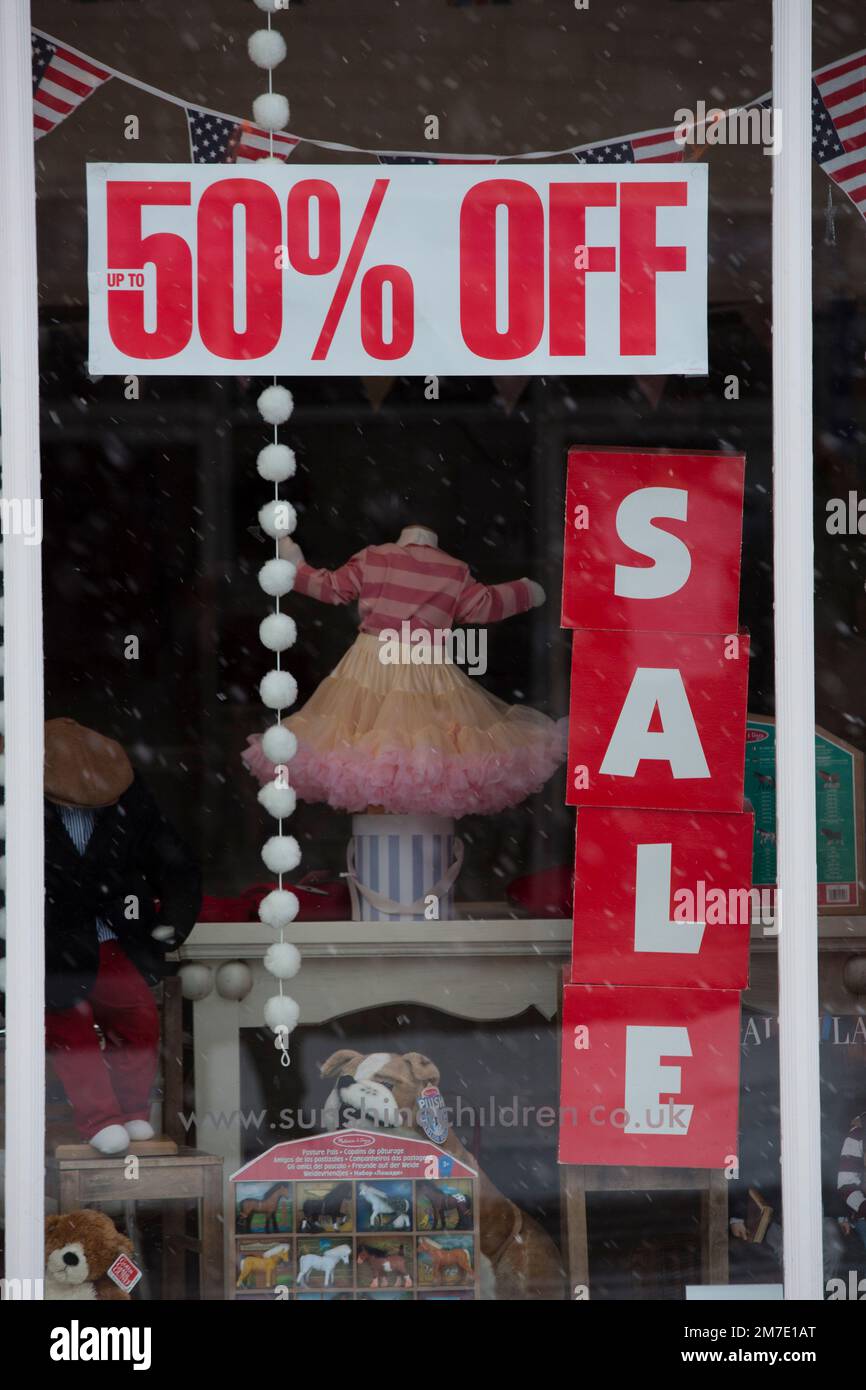 A small shop front with posters advertsiing massive discounts on goods ...