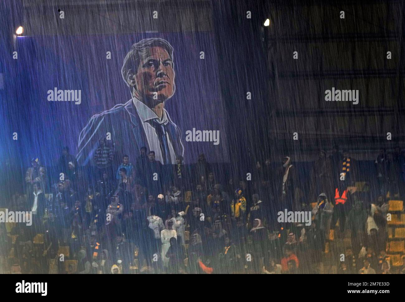 Al-Nassr fans sit during heavy rains under a giant billboard as their ...
