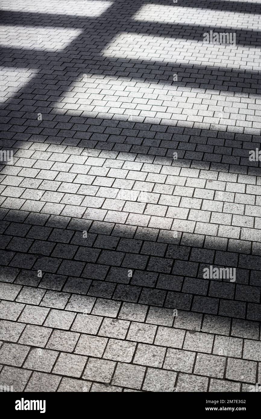Shadow patterns cast across a tiled paved concrete pavement Stock Photo ...