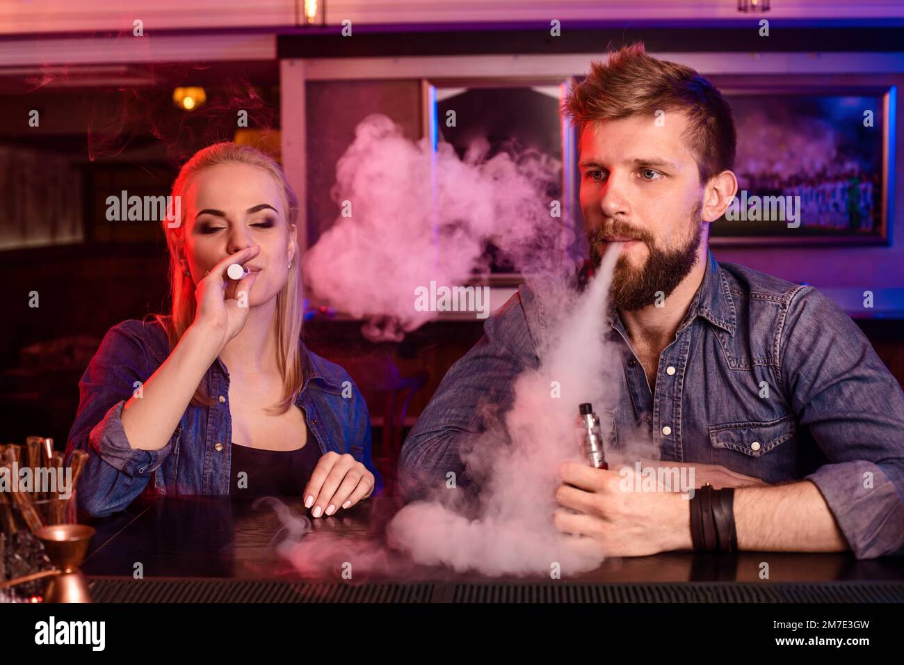 A Man And Woman Smoking Electronic Cigarette In A Vape Bar Stock Photo