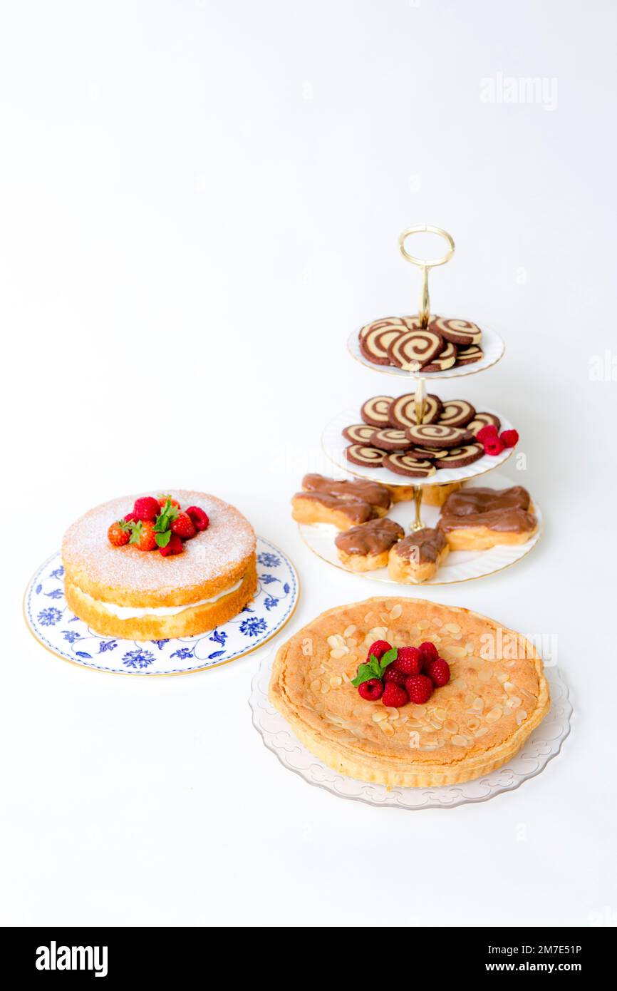 Cakes and pastries, on serving plates in a hite studio background still ...