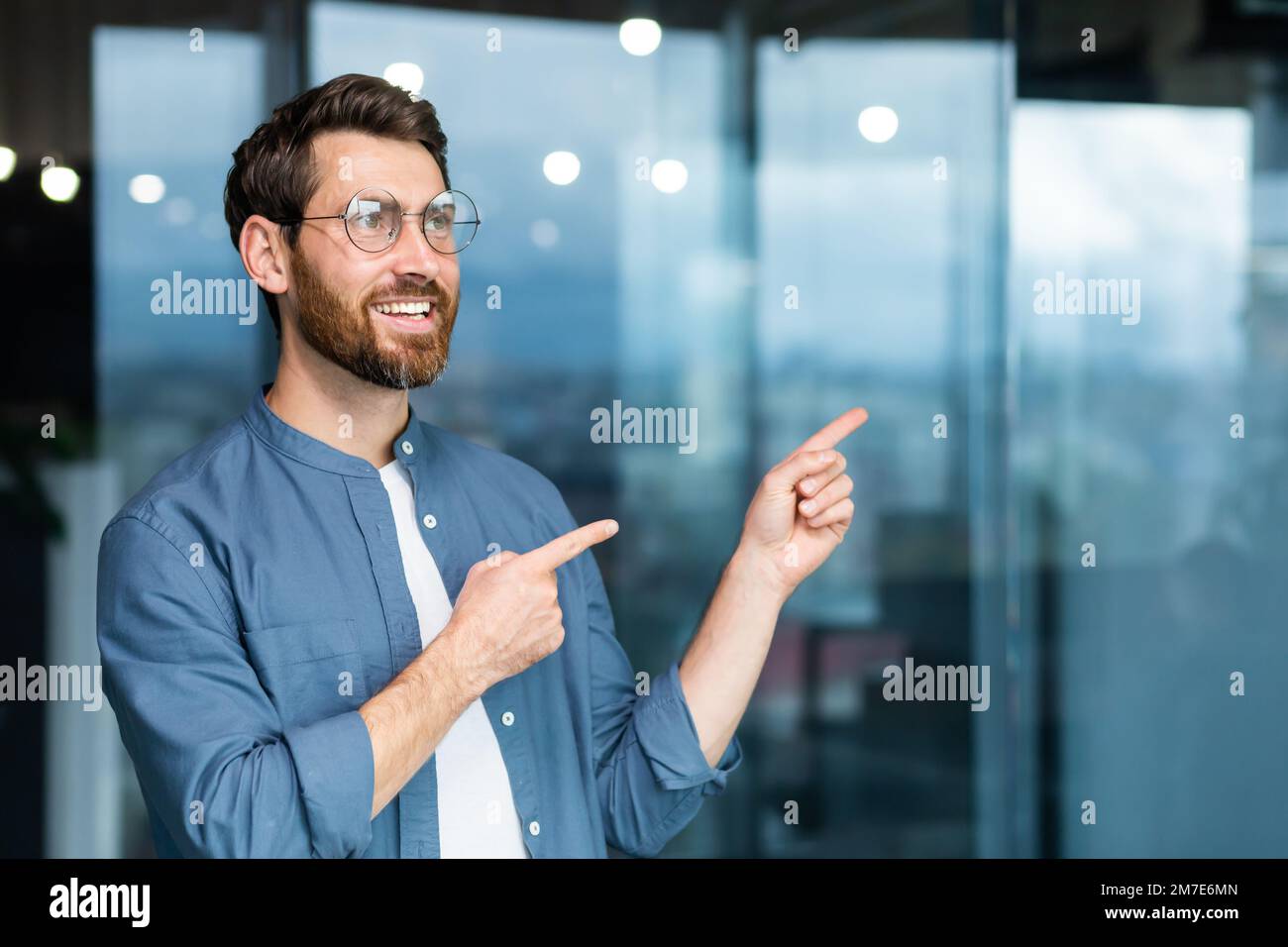 Smiling businessman inside office pointing fingers to direction, happy ...