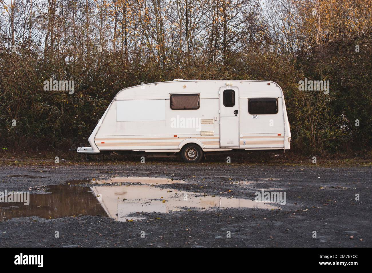 An old caravan parked on the side of a muddy area and abandoned Stock ...
