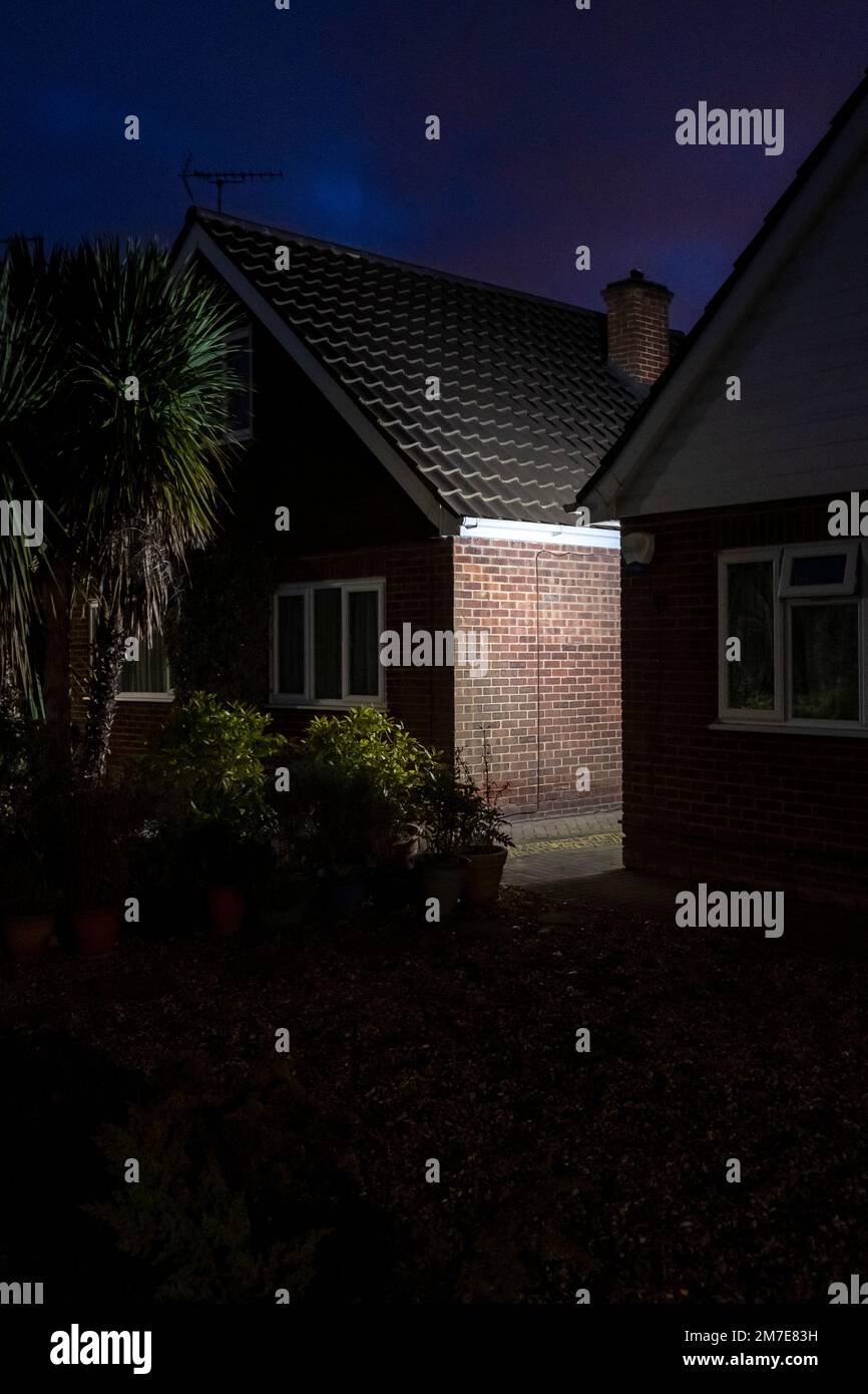 A red brick estate house in the dark of the night with a bright light ...