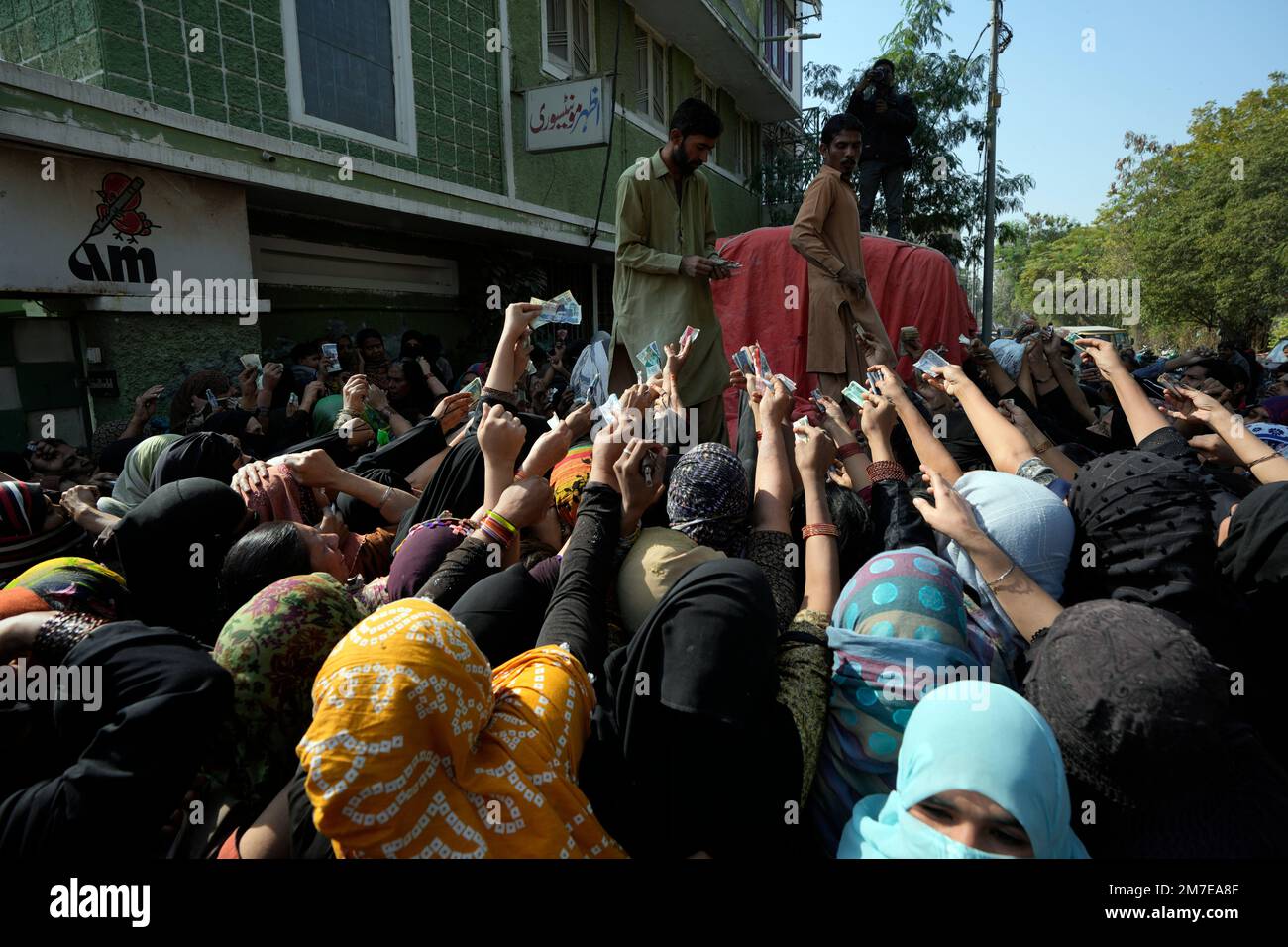 Pakistani women gather to buy subsidized sacks of flour from a sale ...