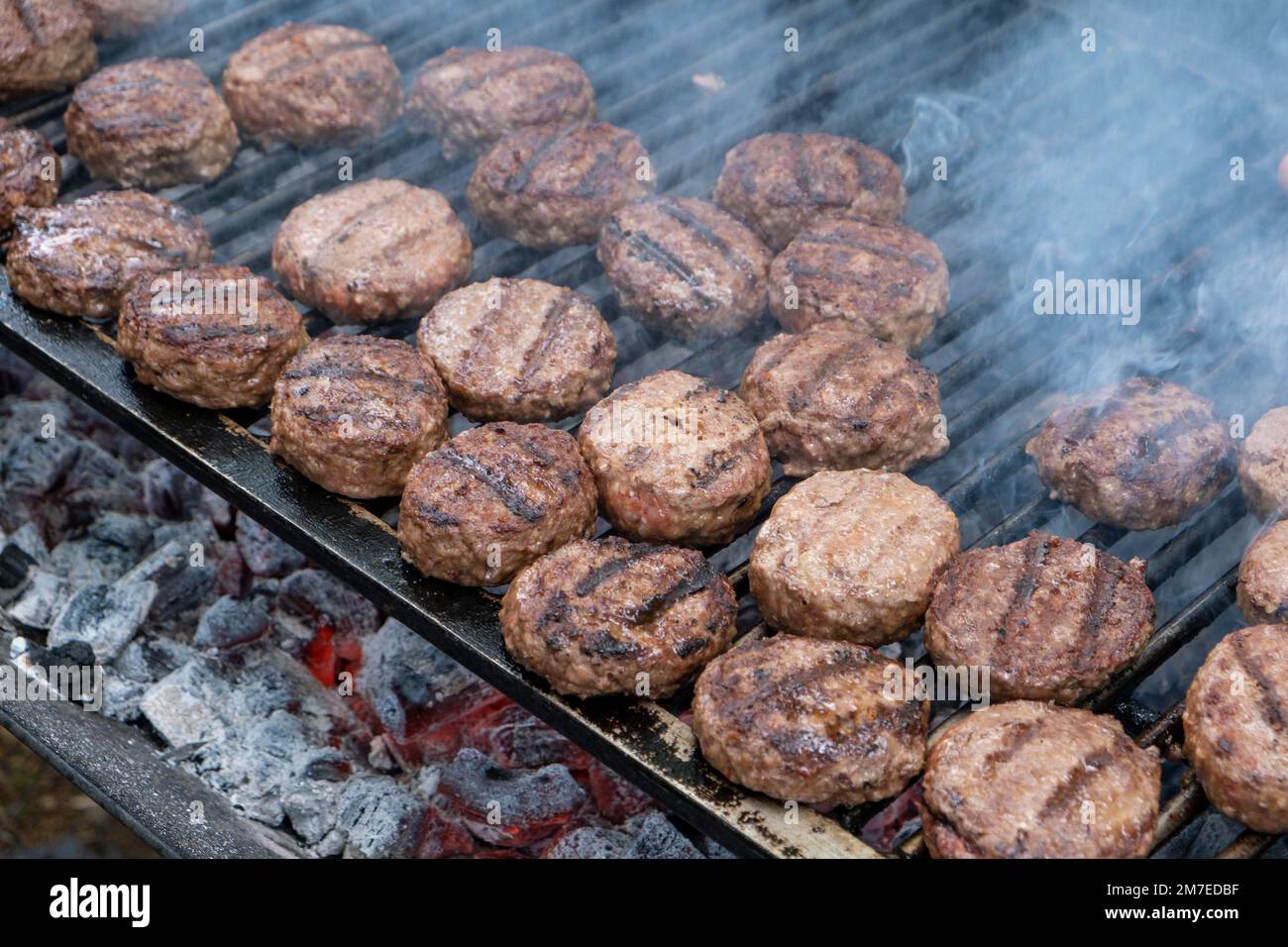 A large outdoor barbecue at a family party with sausages and burgers on ...