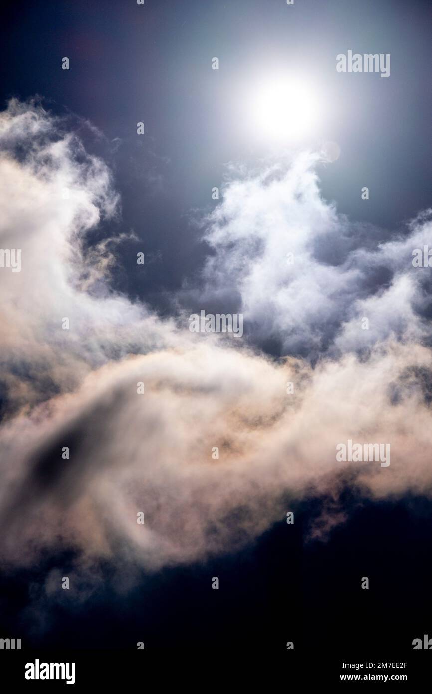 A simple small cloud floating past the bright sun in a blue sky Stock ...