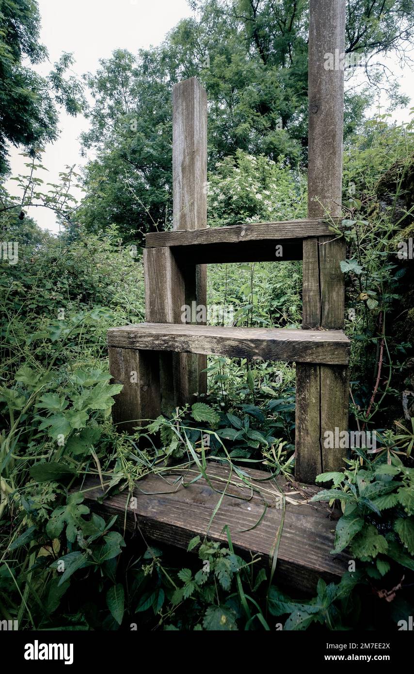 An old wood stile almost lost in the undergrowth on an old country path ...