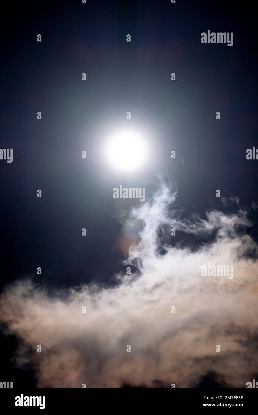 A simple small cloud floating past the bright sun in a blue sky Stock ...