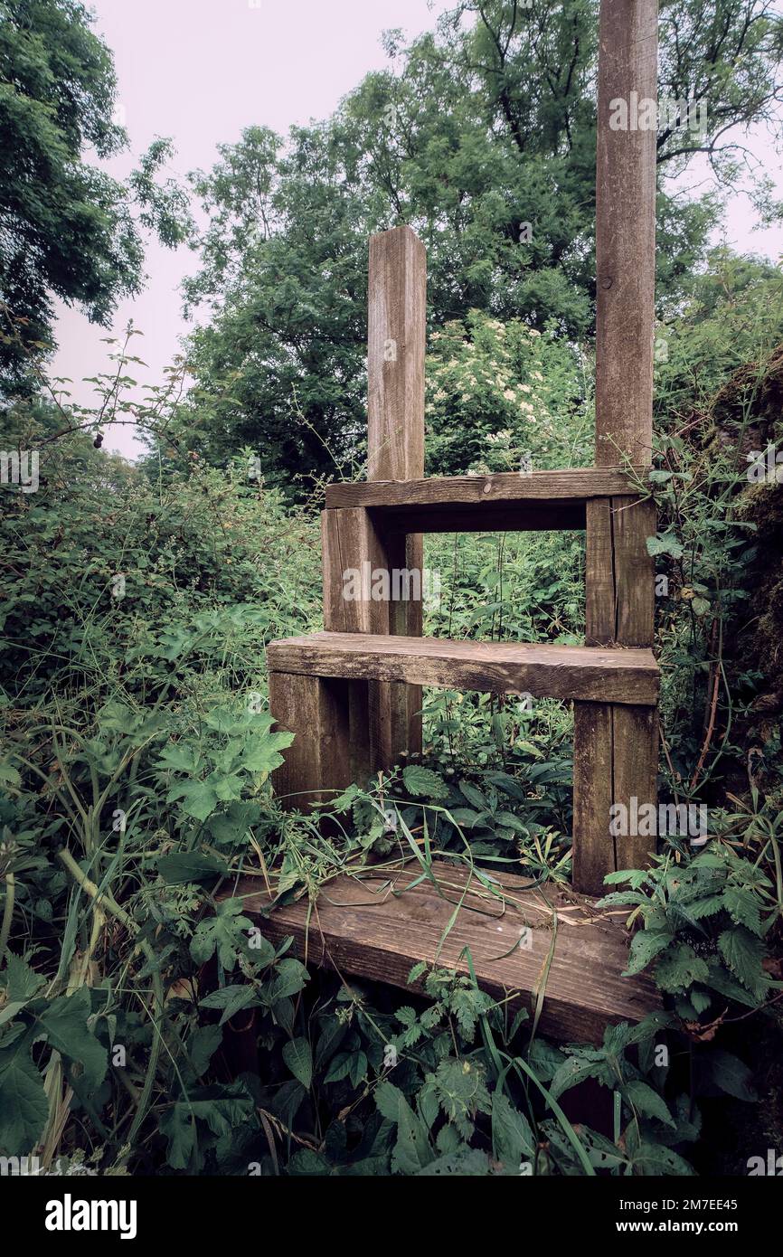 An old wood stile almost lost in the undergrowth on an old country path ...