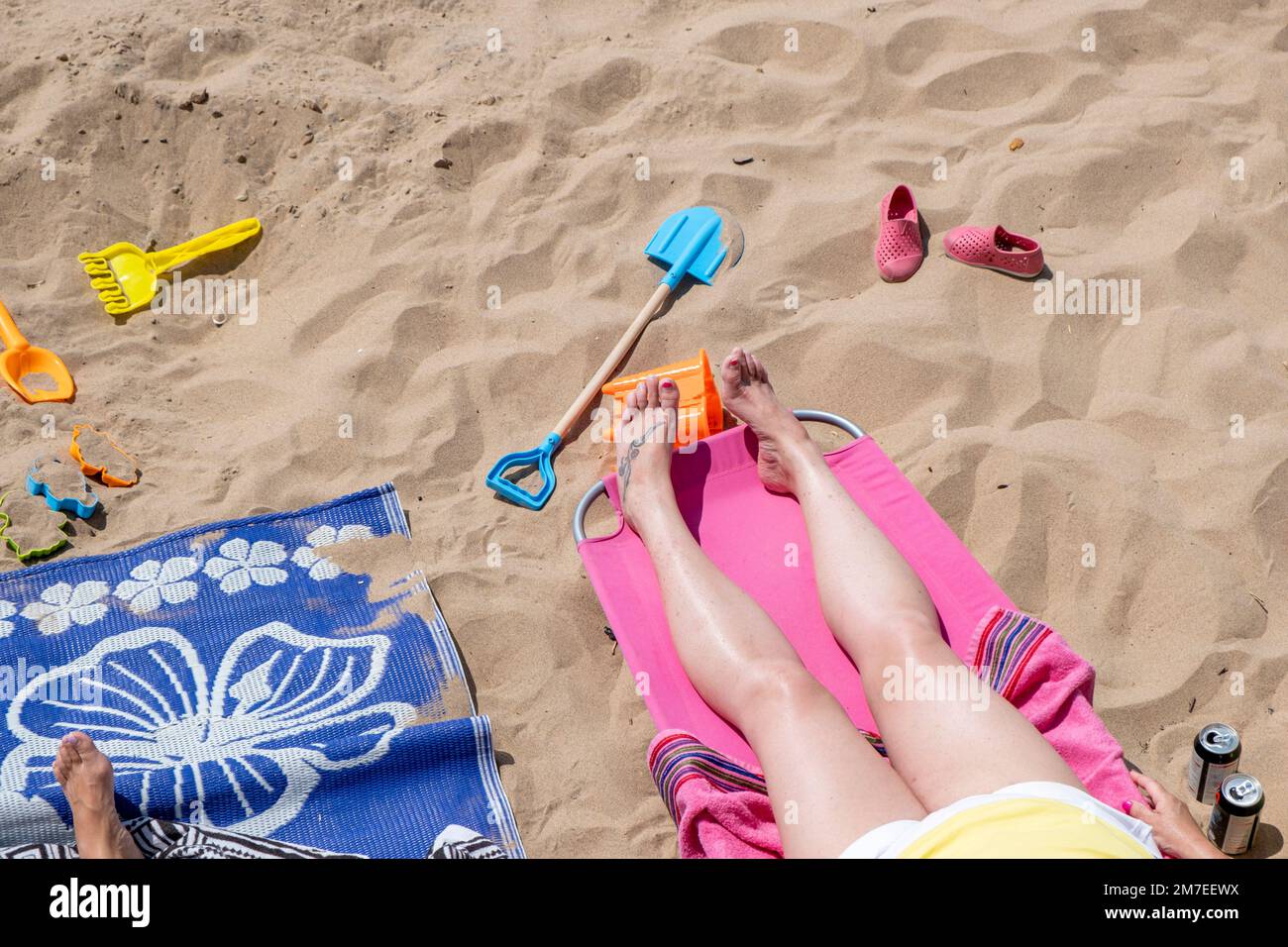 Female feet with legs laying on a towel surrounded by holiday items ...