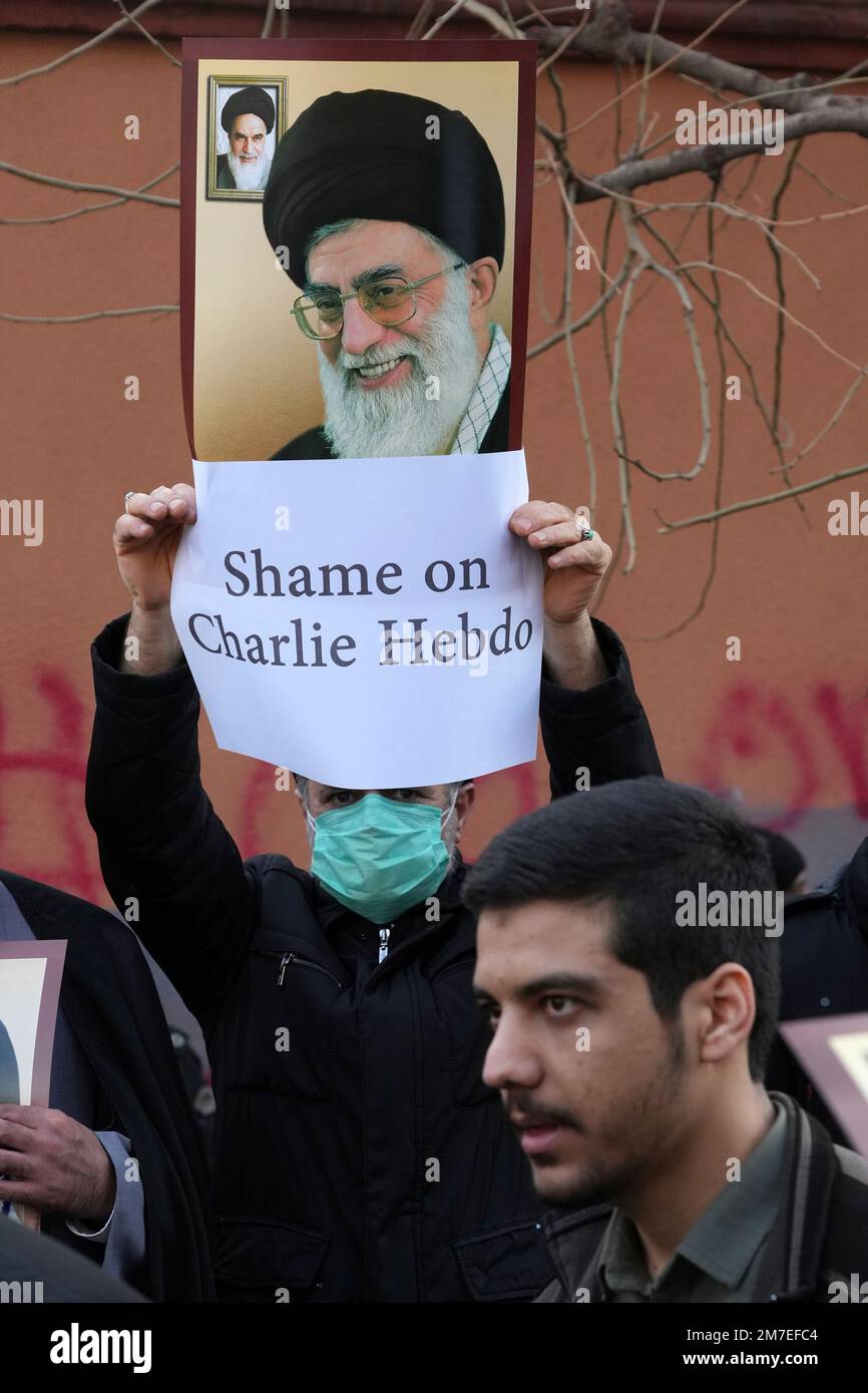 An Iranian demonstrator holds up a sign and a poster showing portraits ...