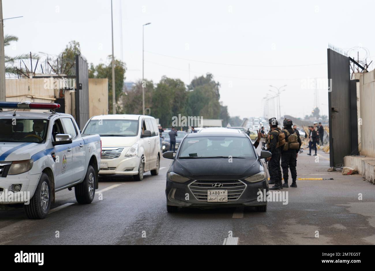 Iraqi security forces stand guard as they check motorists entering the ...