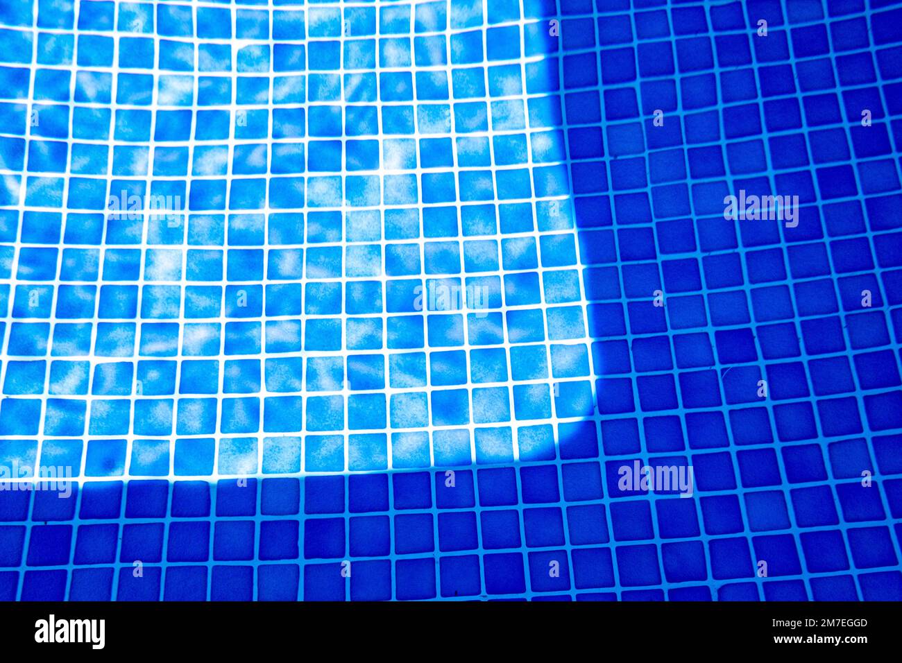 Sunlight reflects on the ripples of the surface of an outdoor swimming ...