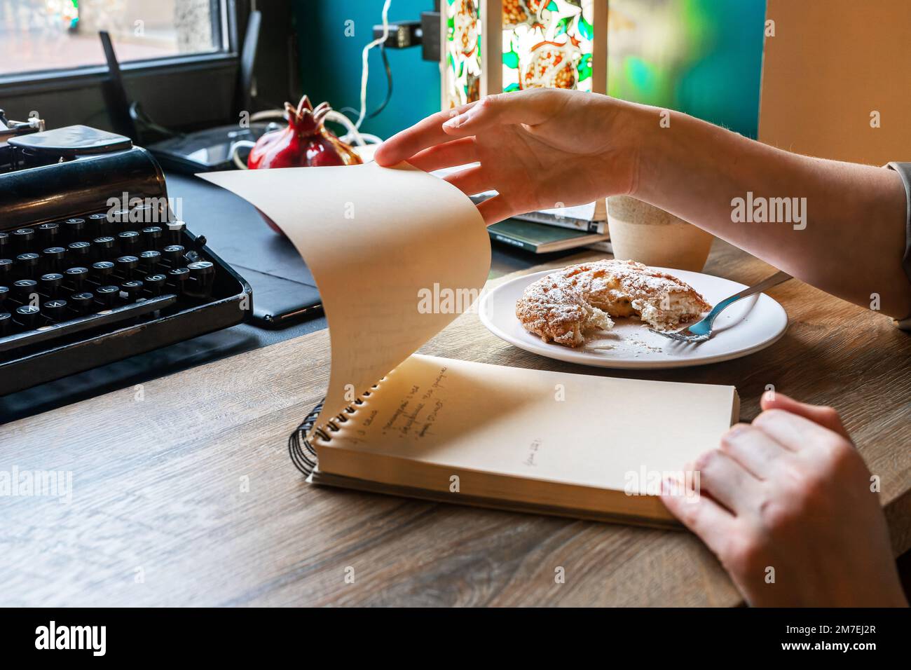 Hand with paper notebook, organizer at cafe desk, wood table, looking ...