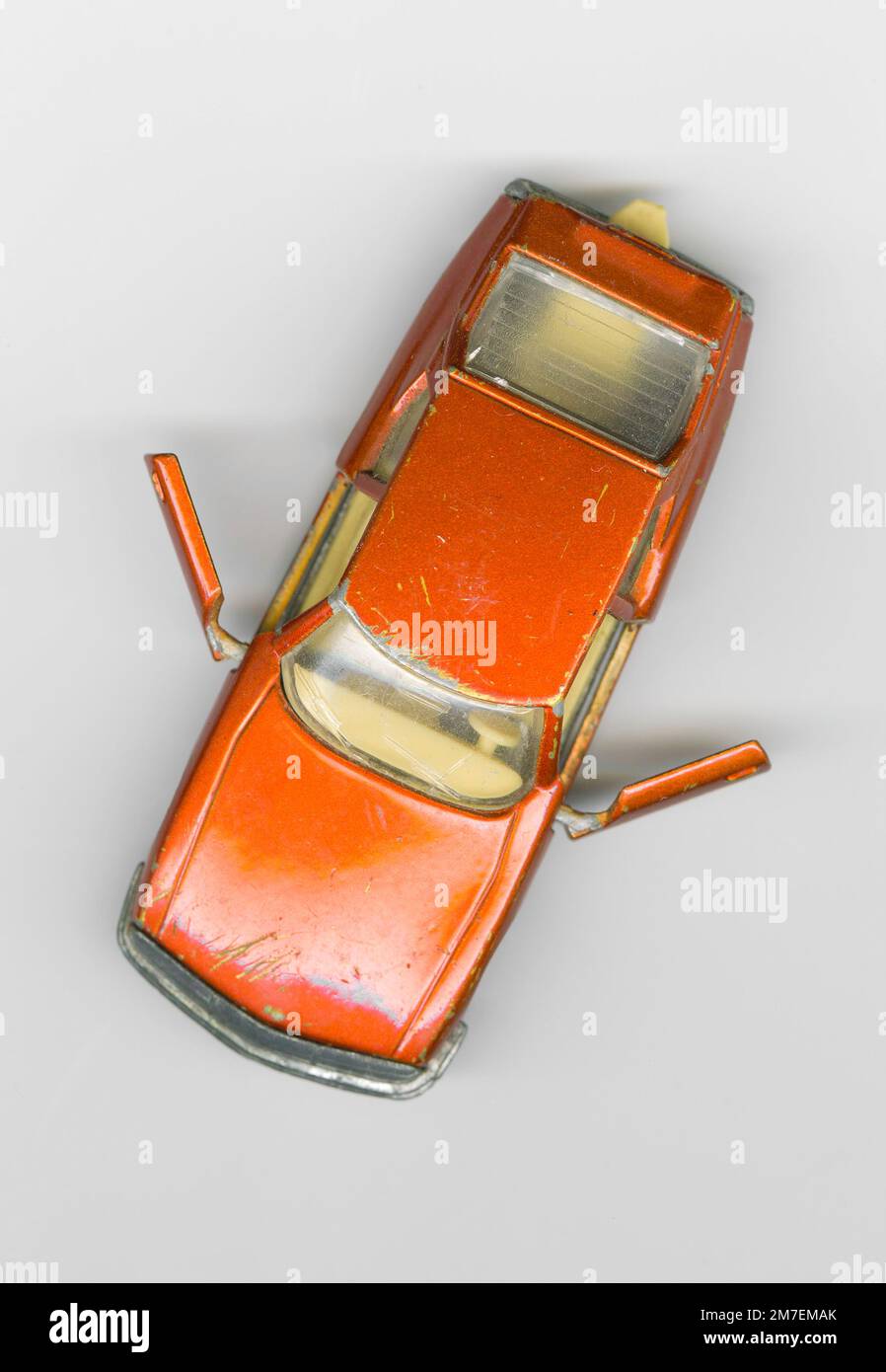 Still life studio shot of an old toy car seen from above in orange ...