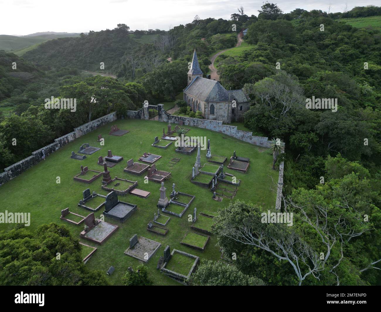 An aerial view of an old church in the forest with graves surrounded by ...