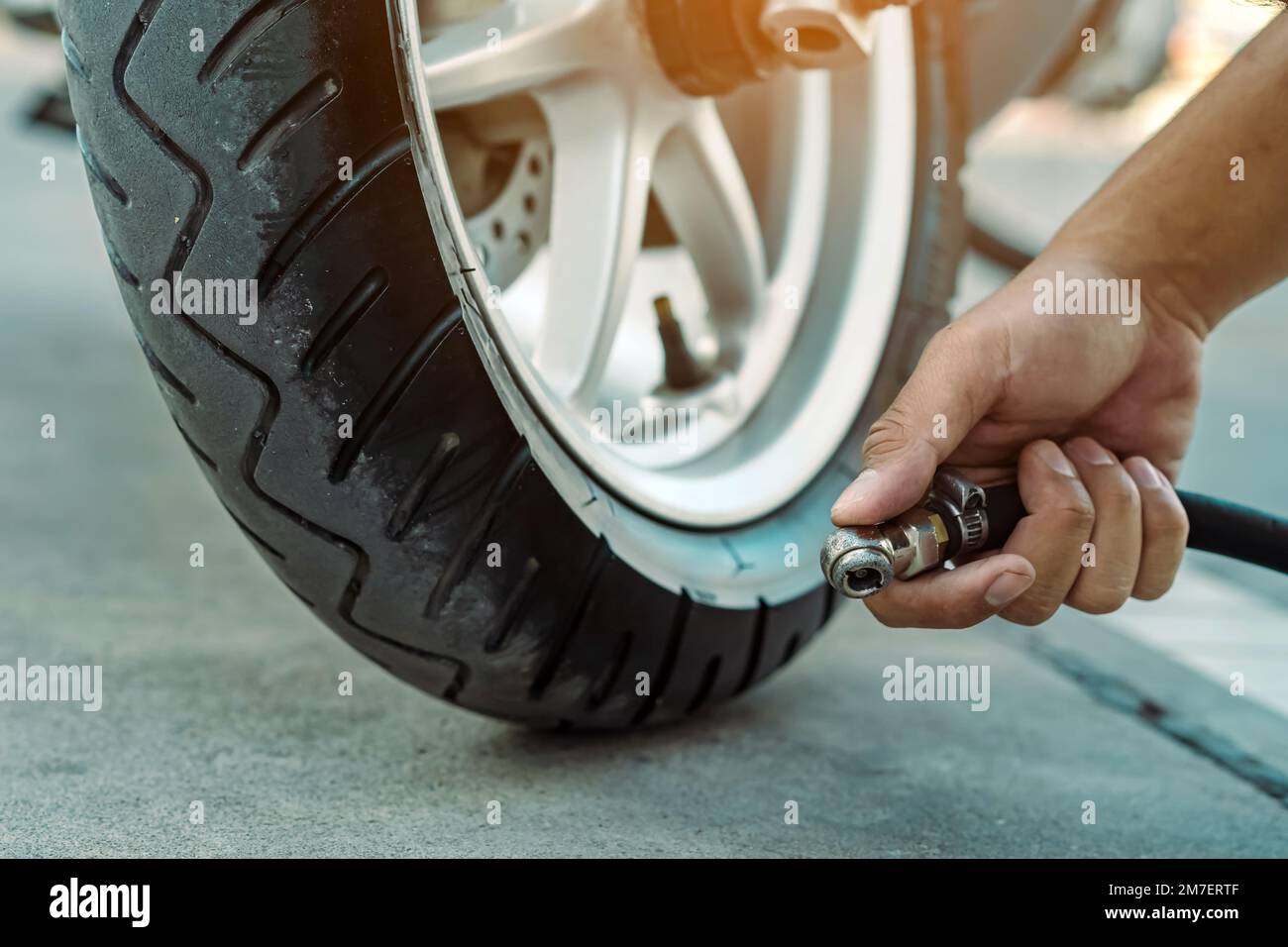 Hands of man check inflator pressure and inflates a tire on motorcycle ...