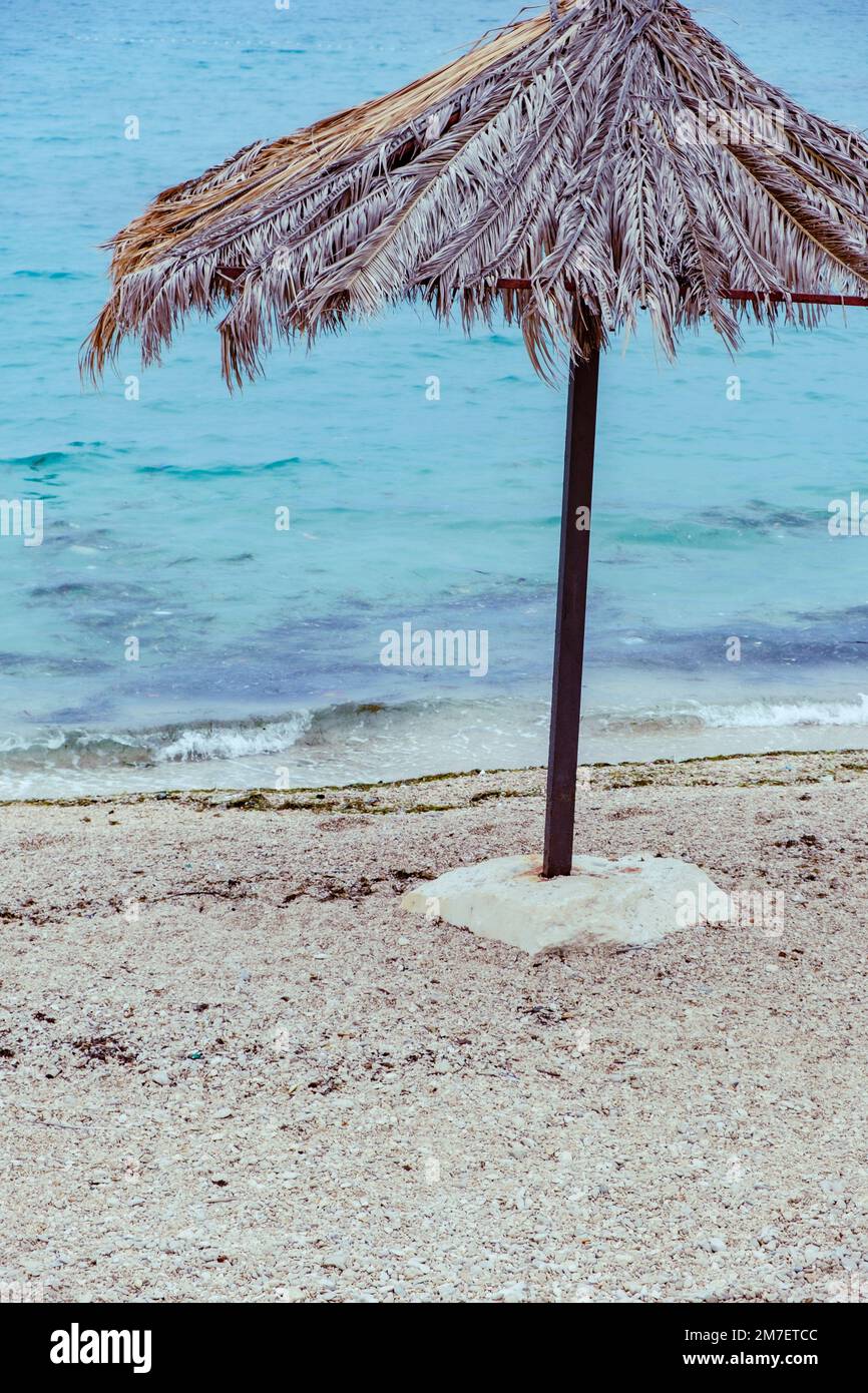A single straw and reed parasol on an empty beach in Croatia Stock ...