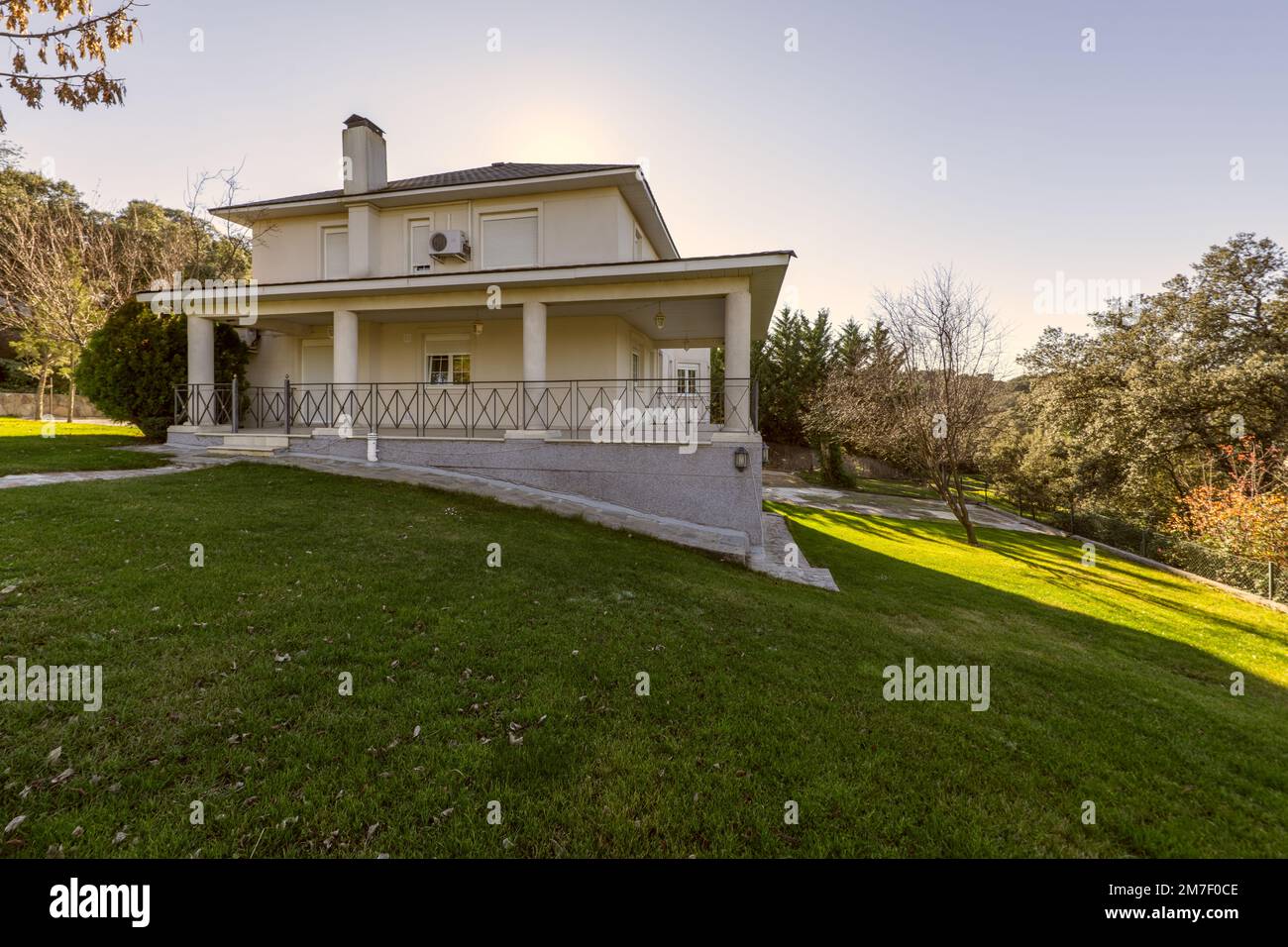 Detached residential single-family house on a sloping lot with grass ...
