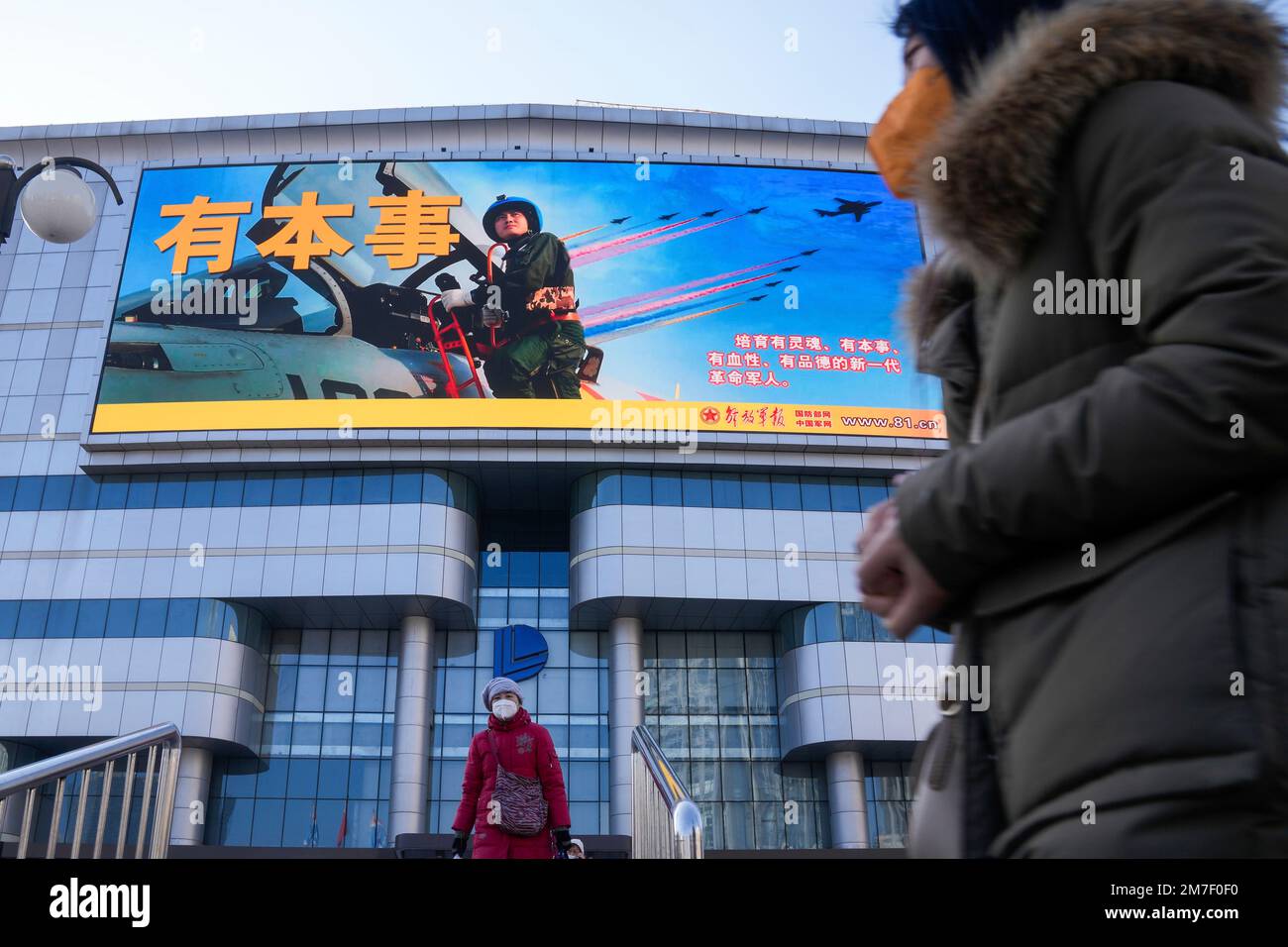 Residents wearing face masks walk by a large screen showing the Chinese ...