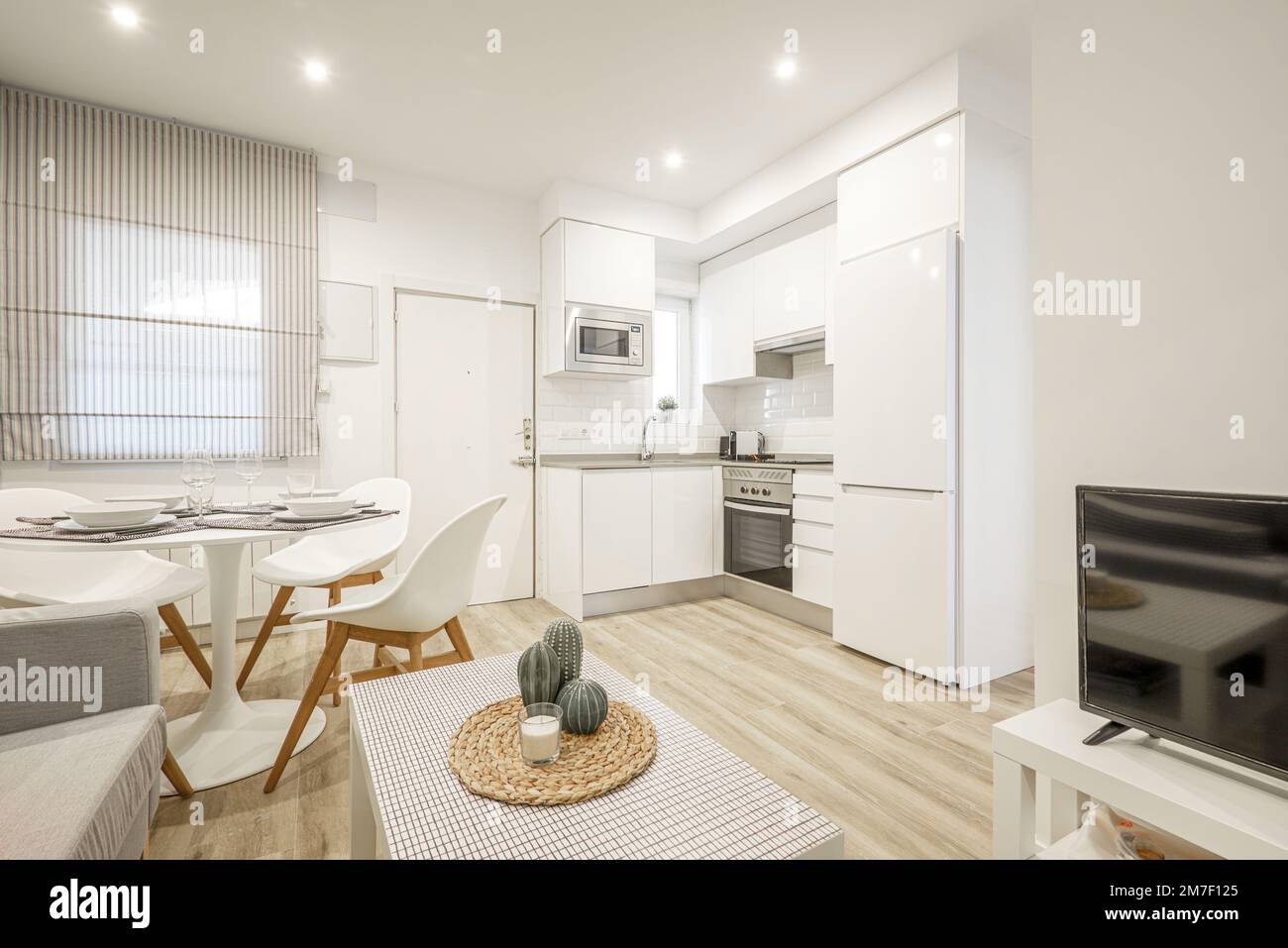 Studio apartment with an open plan kitchen with white cabinets and a ...