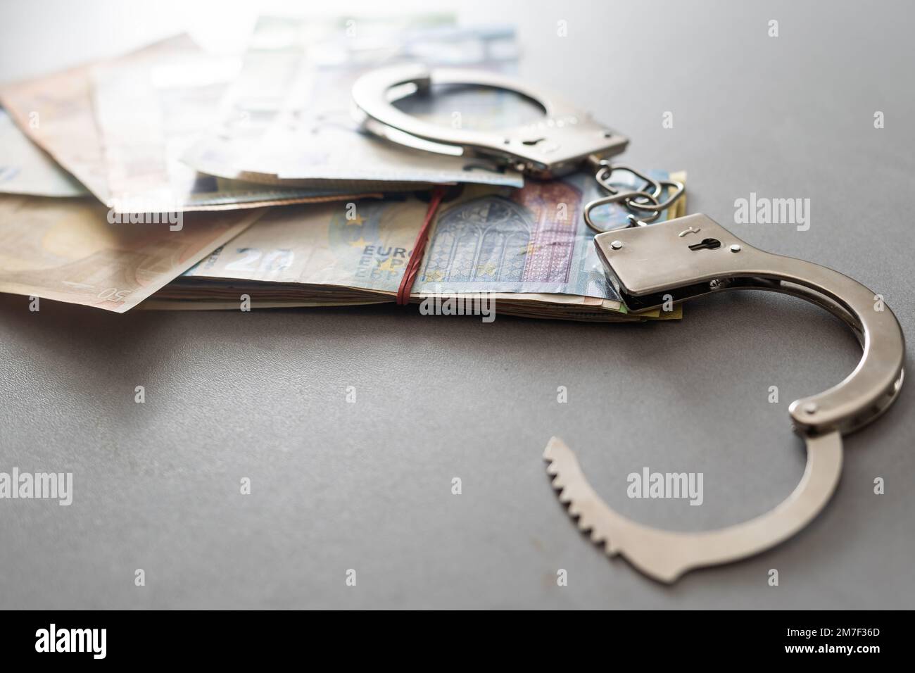 silver handcuffs on many large euro notes Stock Photo - Alamy