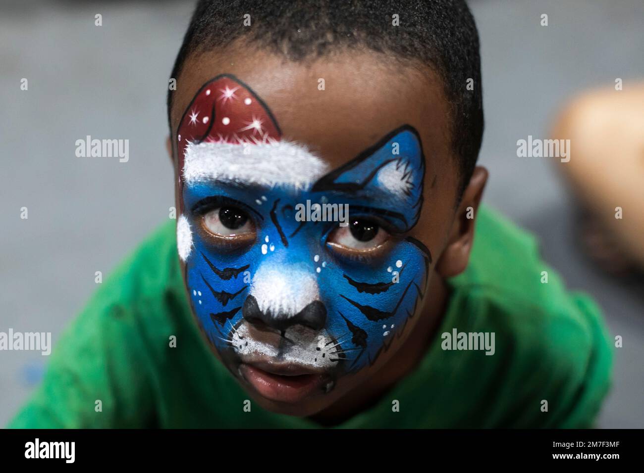 A youth with his face painted as a cat attends a Christmas event with ...