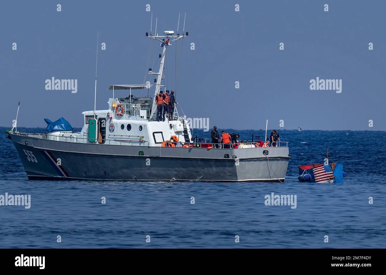 People in a makeshift boat with the U.S. flag painted on the side are ...