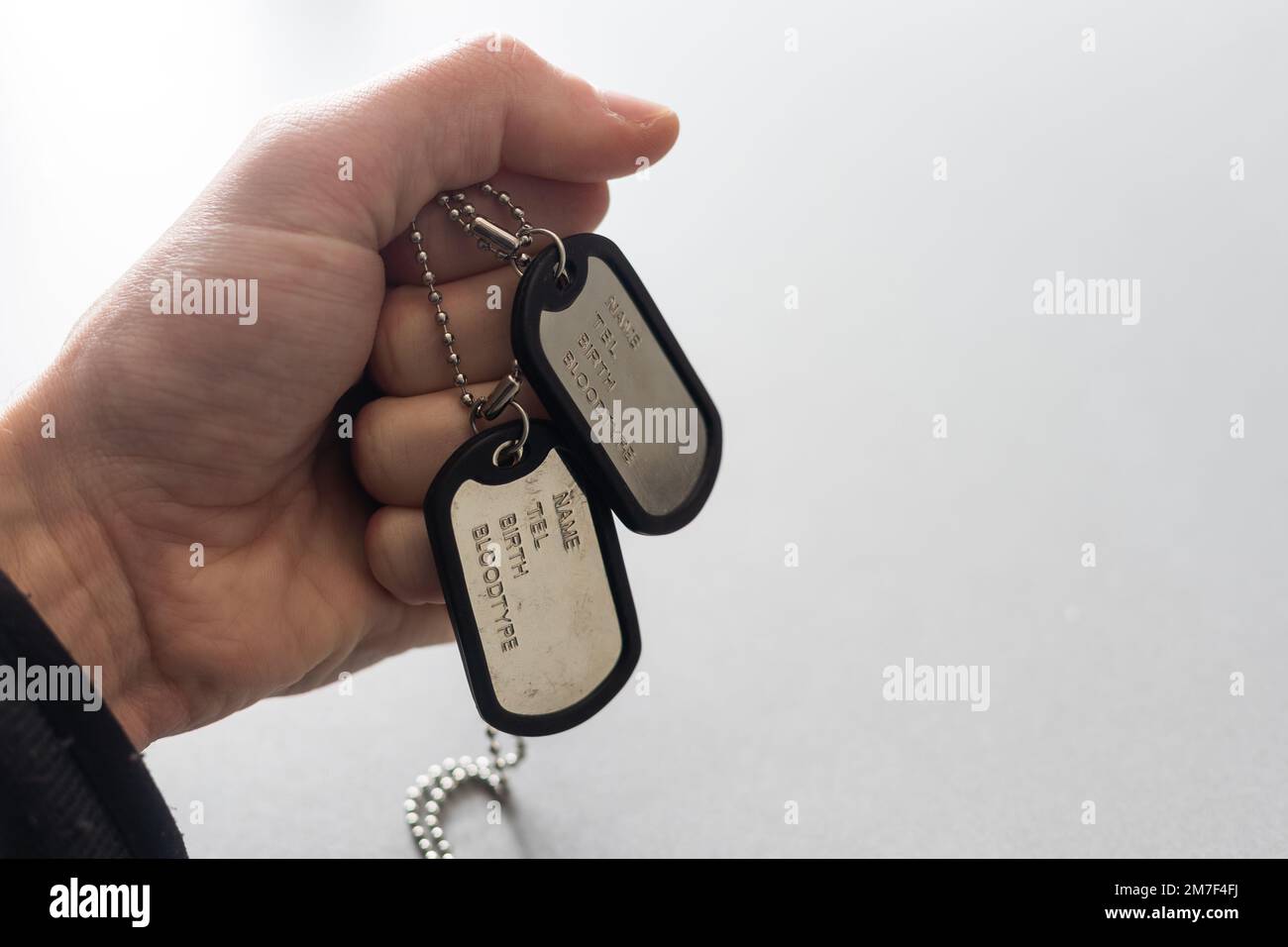 blank army dog tags in hand on white background Stock Photo - Alamy