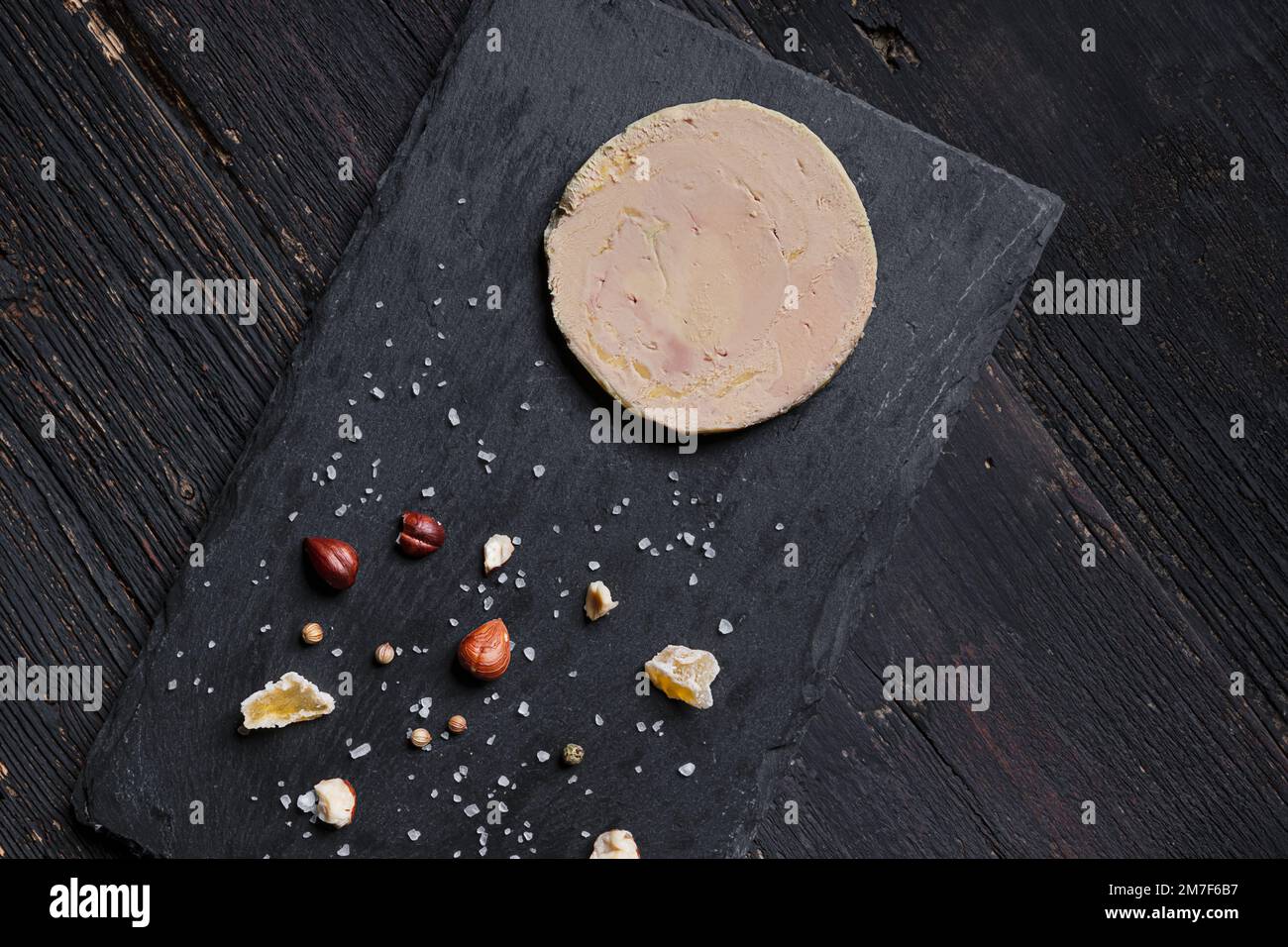 French foie gras on a slate served with nuts, pepper, salt, and dried ...