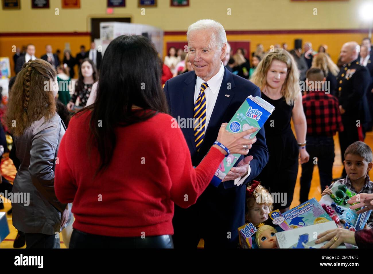 President Joe Biden helps children move donated toys to bins during a ...