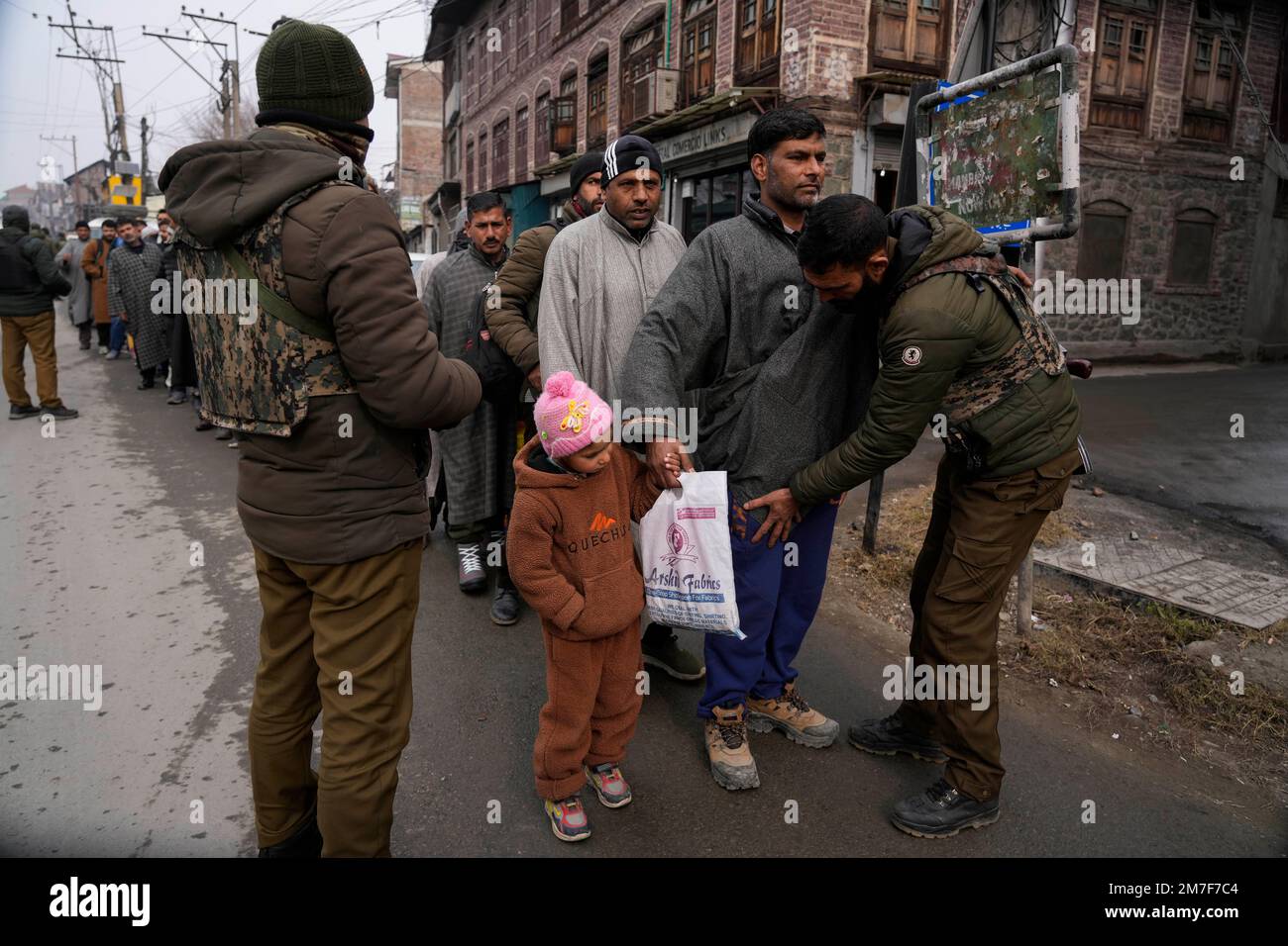 A child looks on as Indian policemen frisk Kashmiri pedestrians during ...
