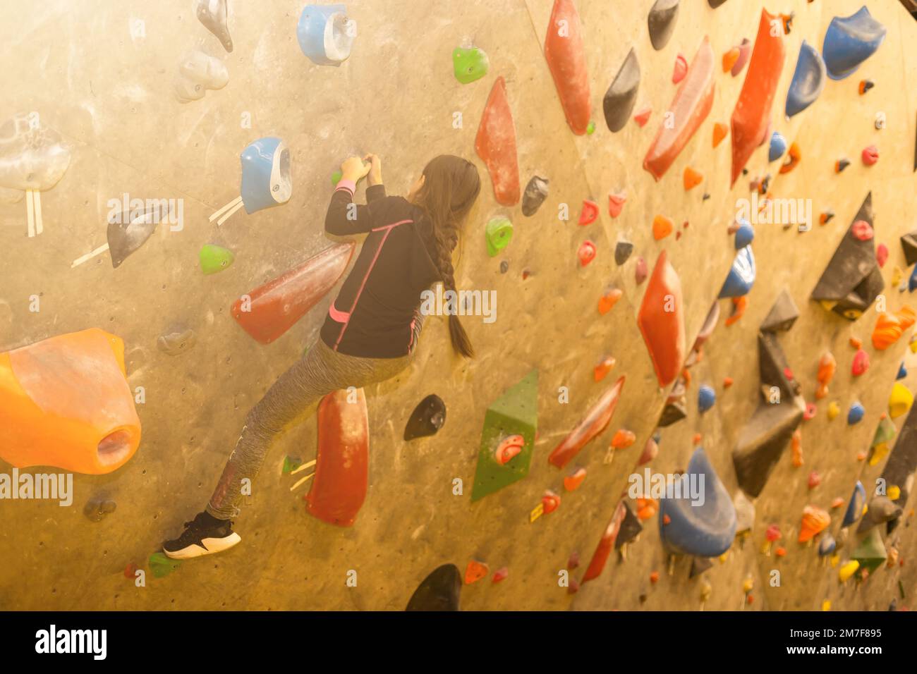 Teenage girl at indoor climbing wall. Kid having fun at bouldering wall ...