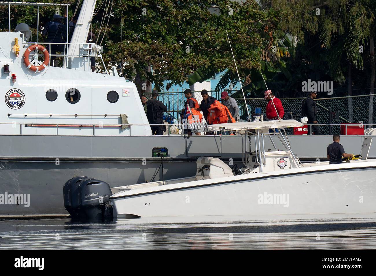 Three people who were captured in a makeshift boat, with the U.S. flag ...