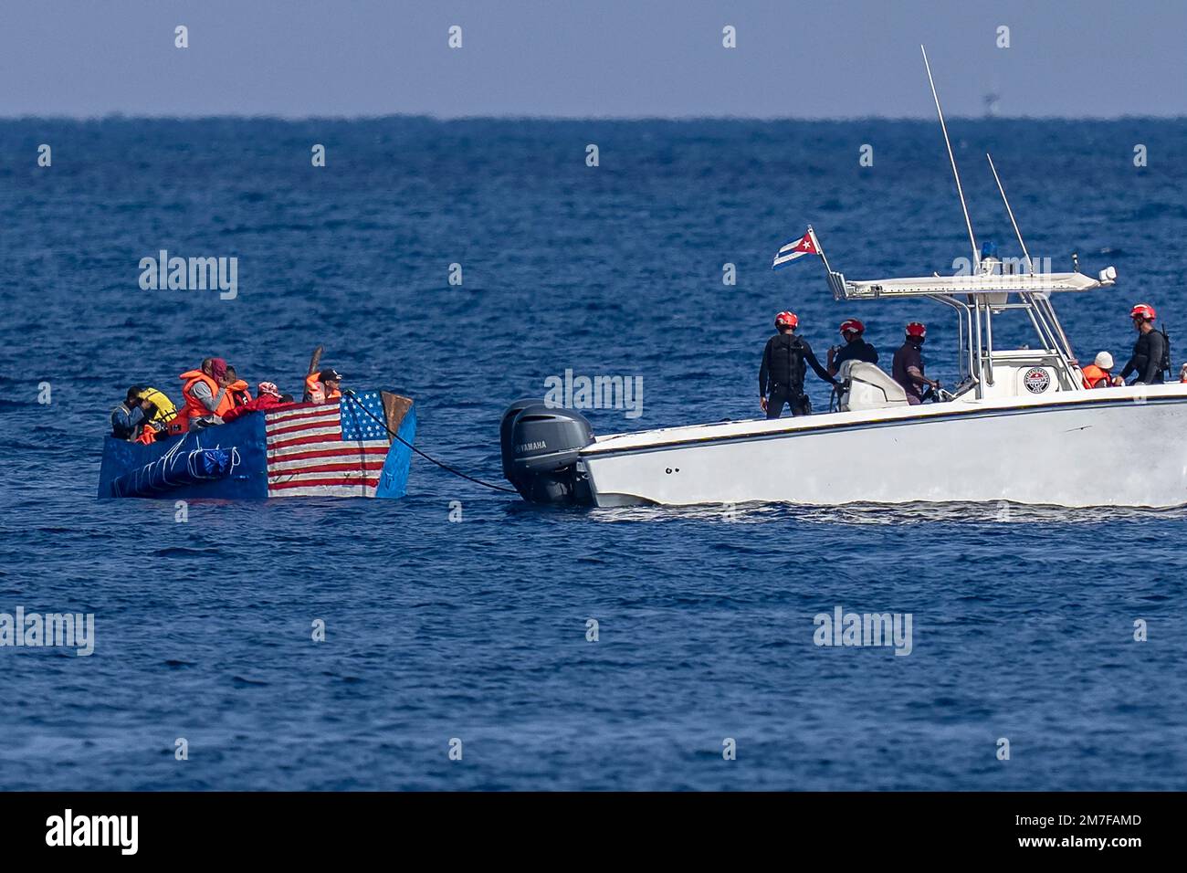 People in a makeshift boat with the U.S. flag painted on the side are ...