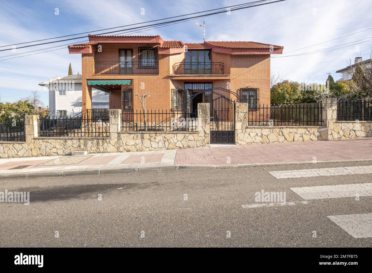 Detached house with a plot with a stone and metal perimeter fence seen ...