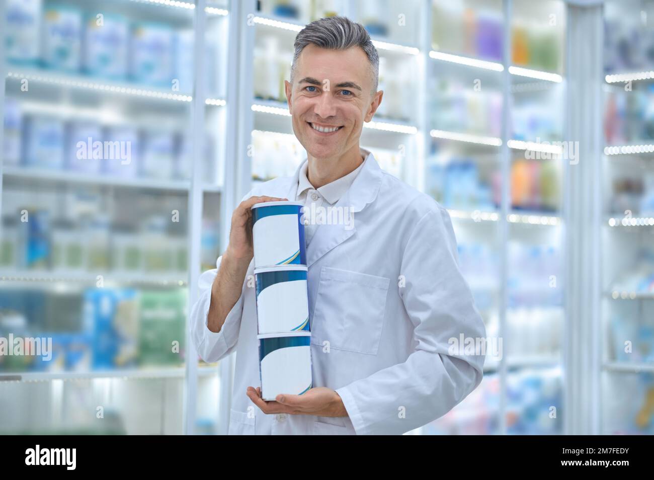 Smiling male pharmacist with cans of infant milk in hands Stock Photo ...