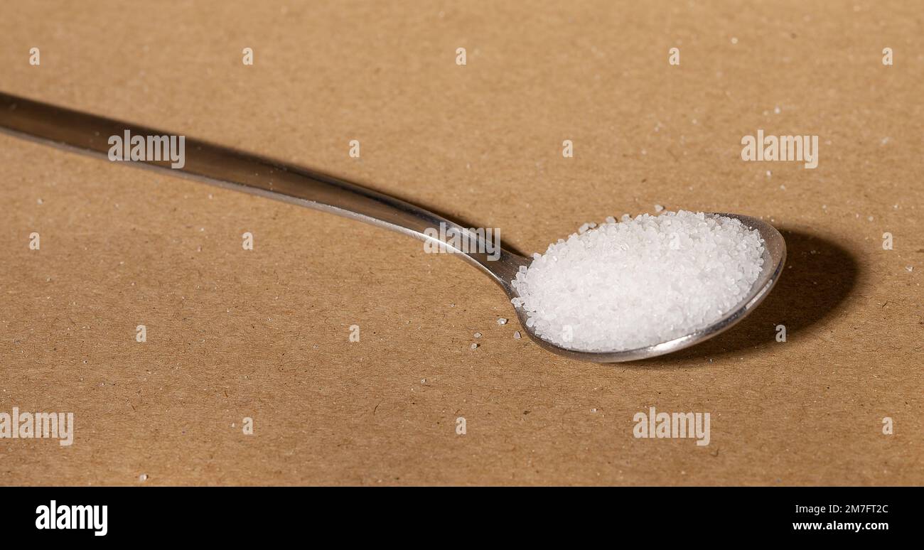 Spoon filled with beet sugar, white sweetener crystals. Metal teaspoon ...