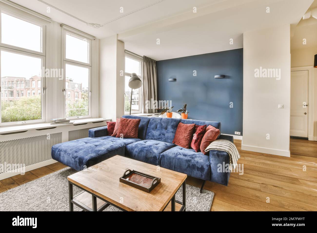 a living room with blue couches and white walls, hardwood flooring and ...