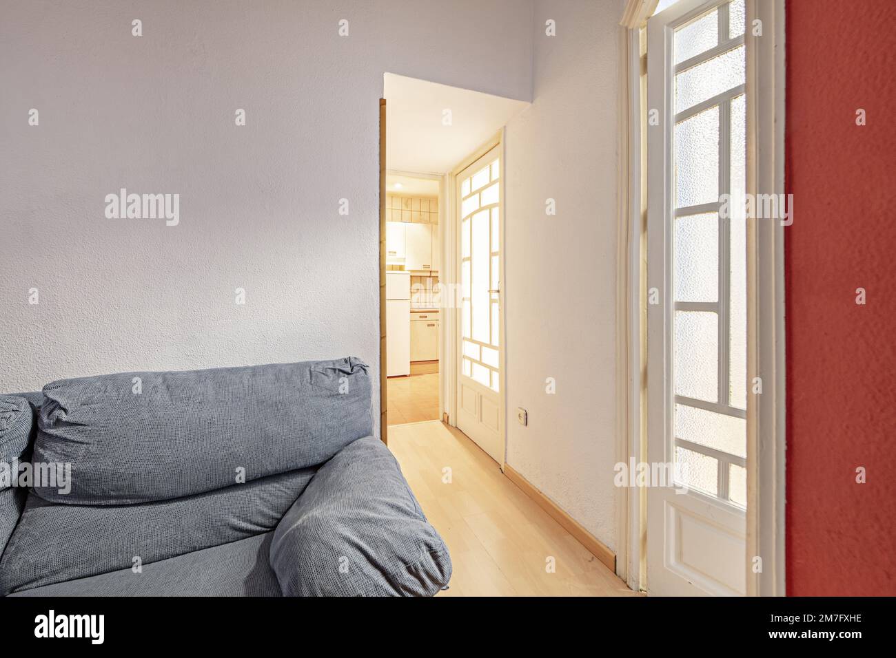 Corner of a living room with a sofa next to a corridor leading to a ...