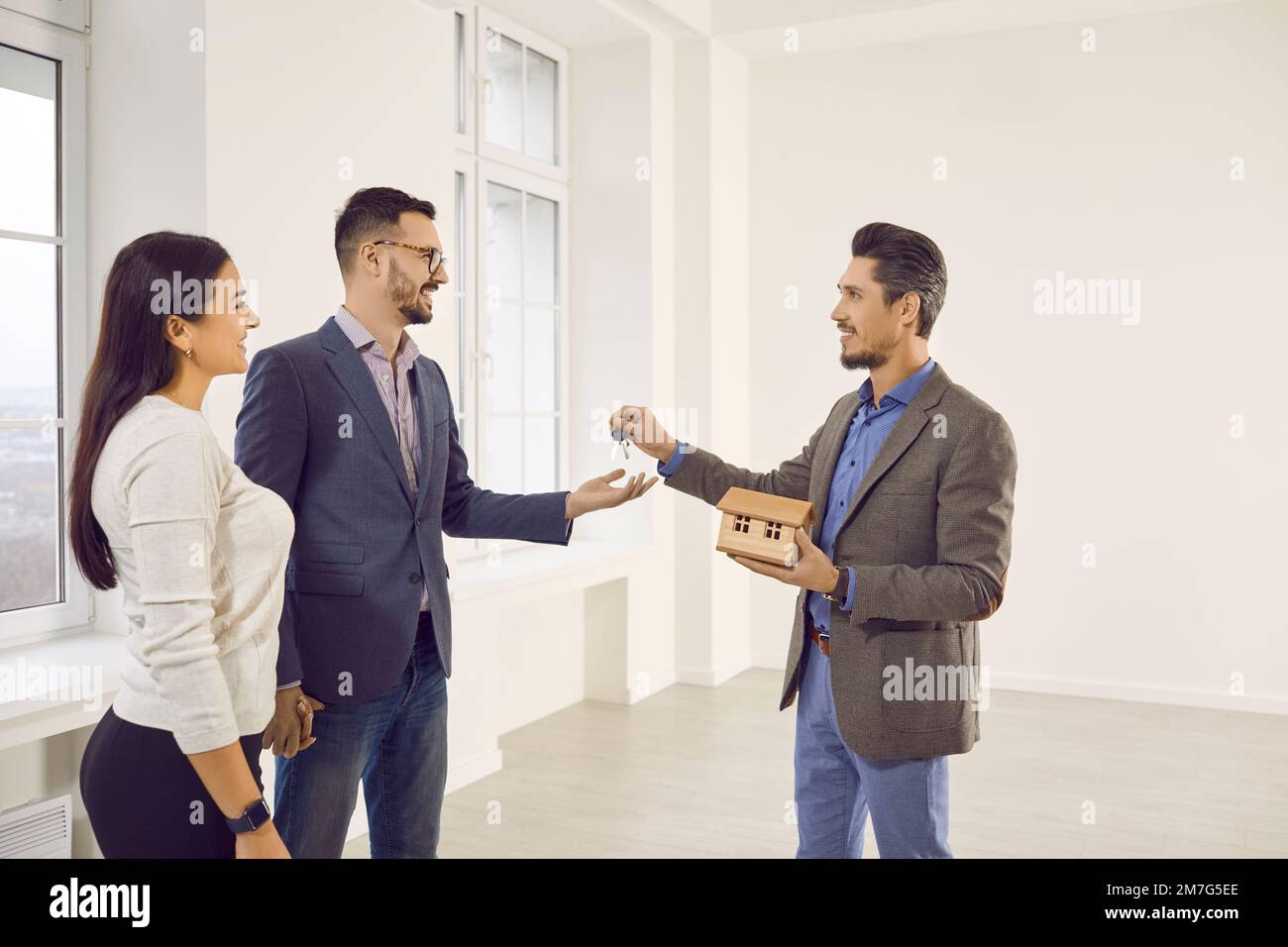 Male real estate agent giving house keys to happy married couple Stock ...