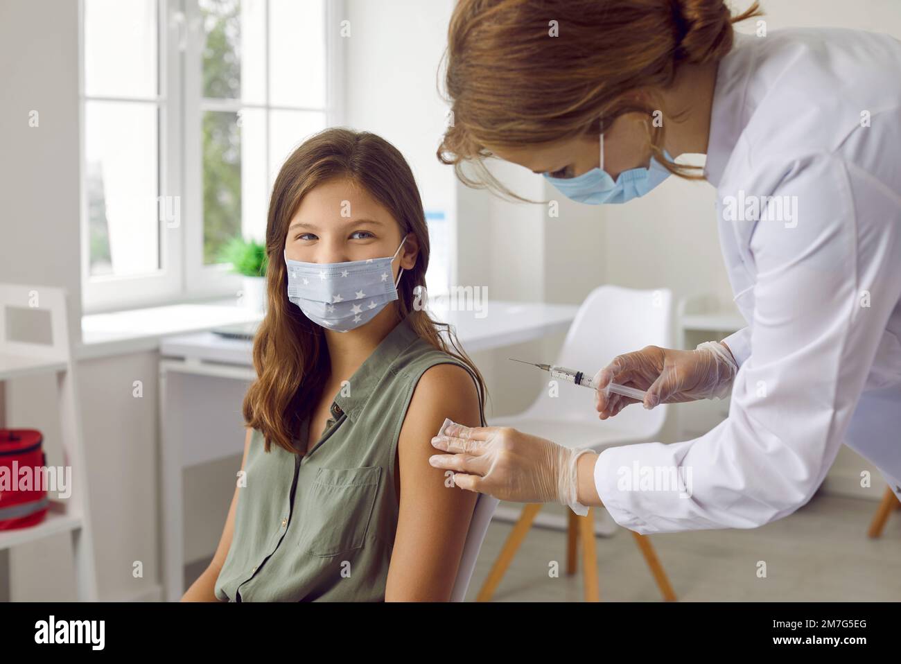 Smiling child in mask receiving vaccine shot against covid infection at ...